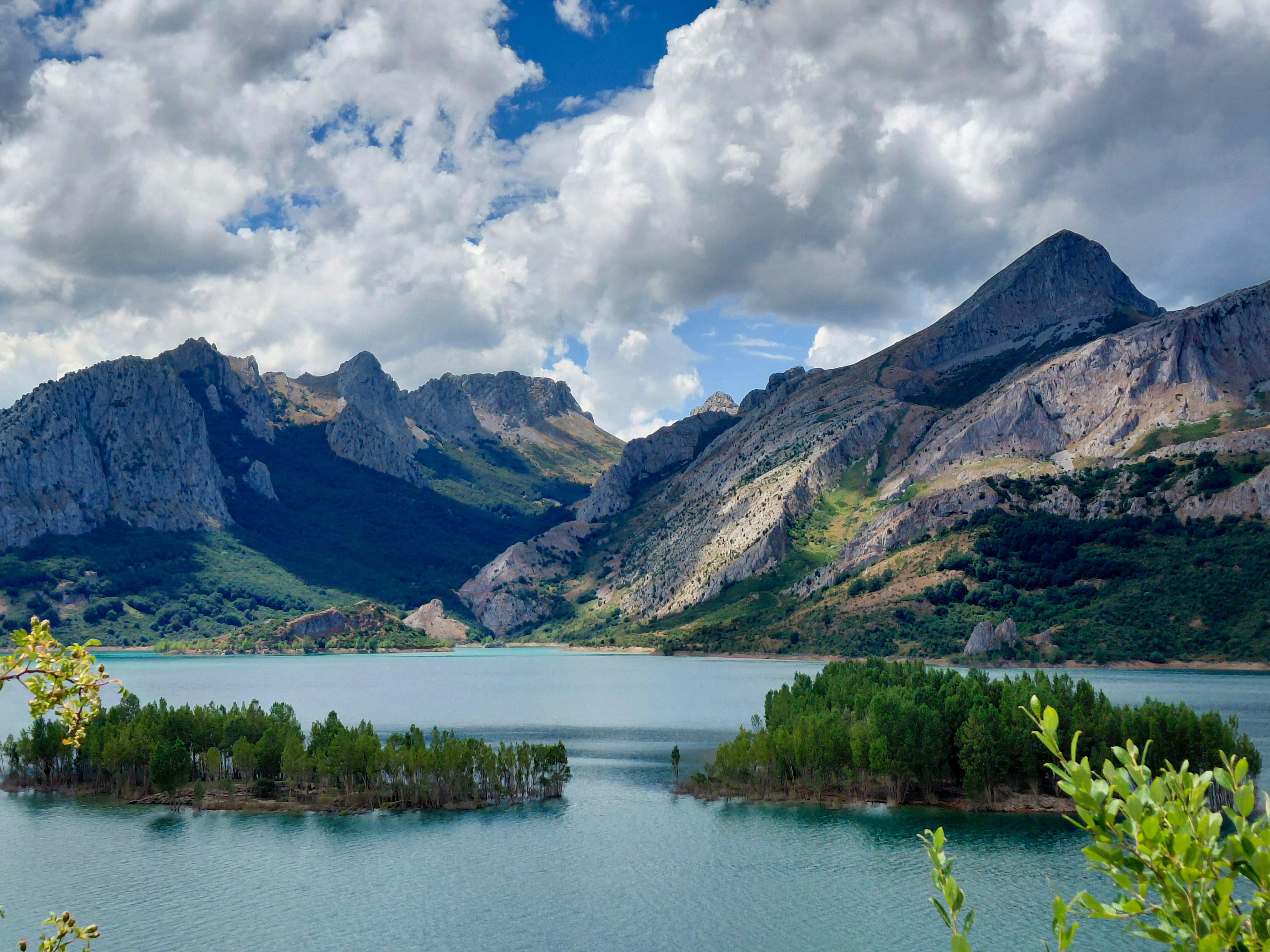 Majestic mountains overlook a serene blue lake with islands.