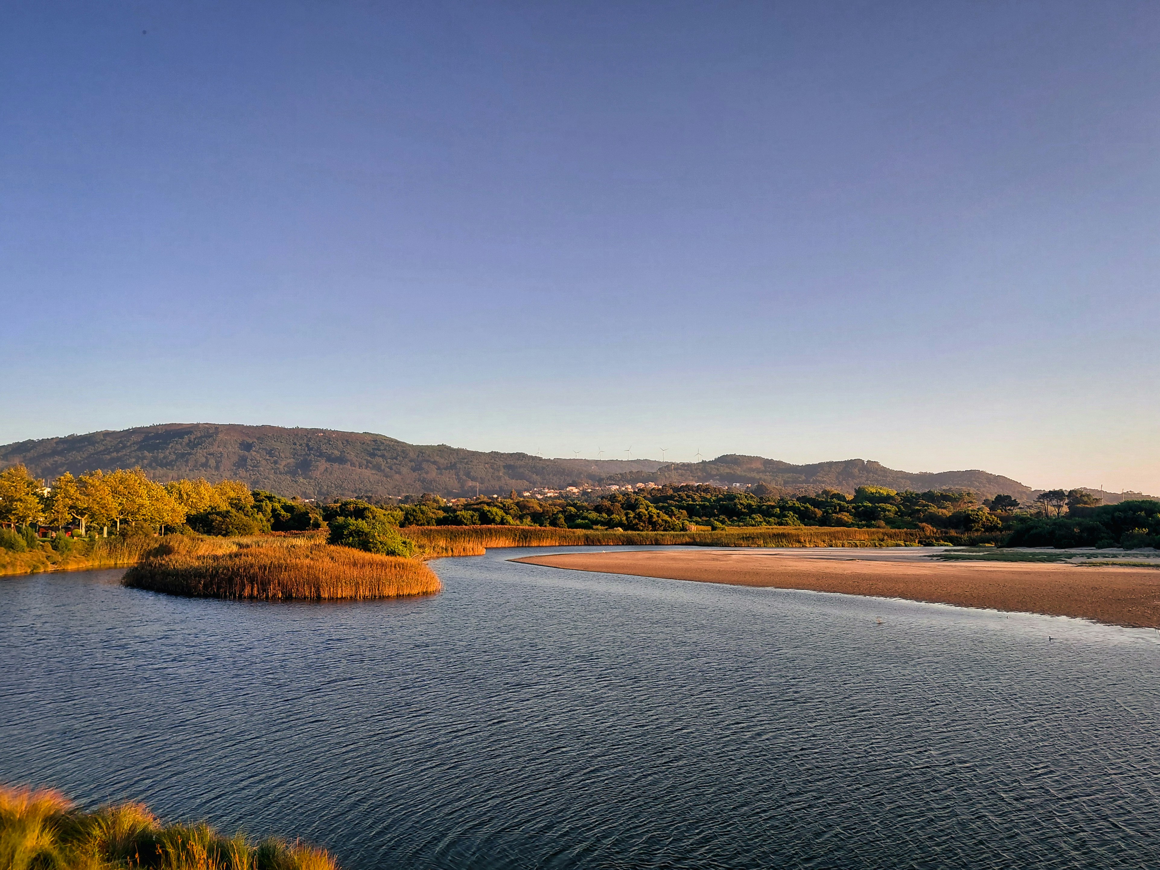 Calm river flowing through a landscape at sunset.
