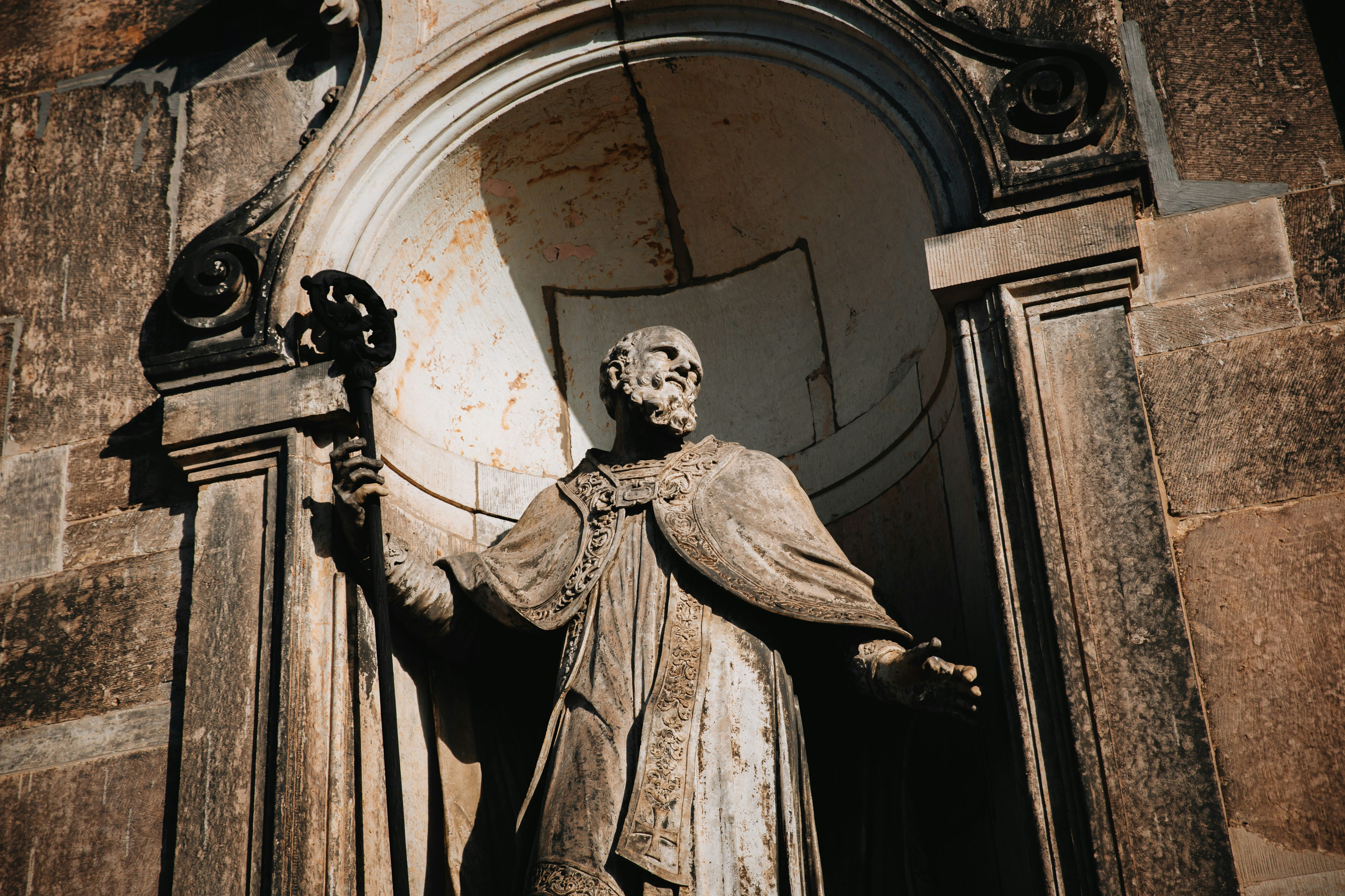 Guarded Gaze: A Bronze Saint Beneath Stone Arches