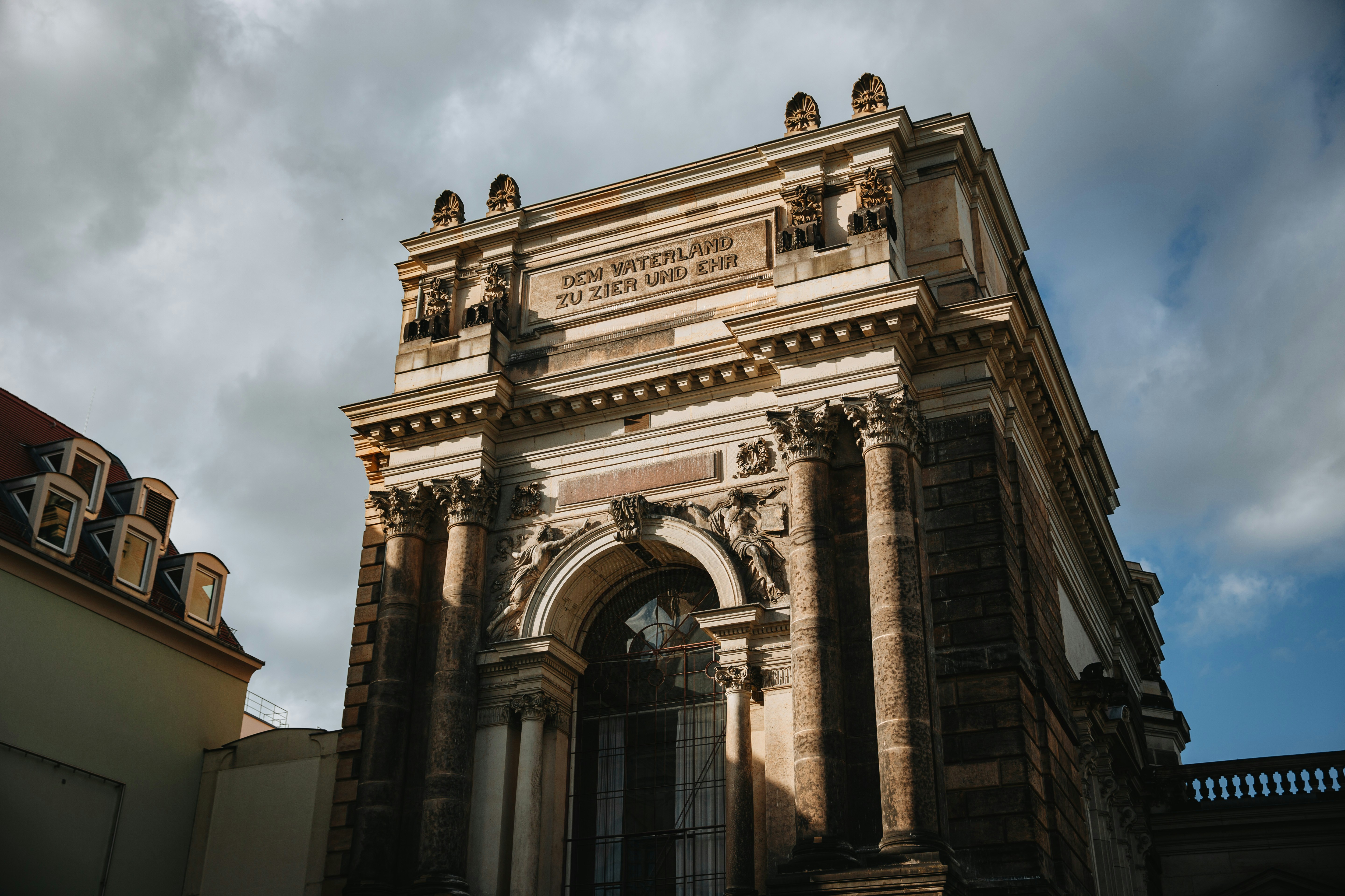 Grand historical building featuring intricate architectural details and a dramatic sky backdrop.