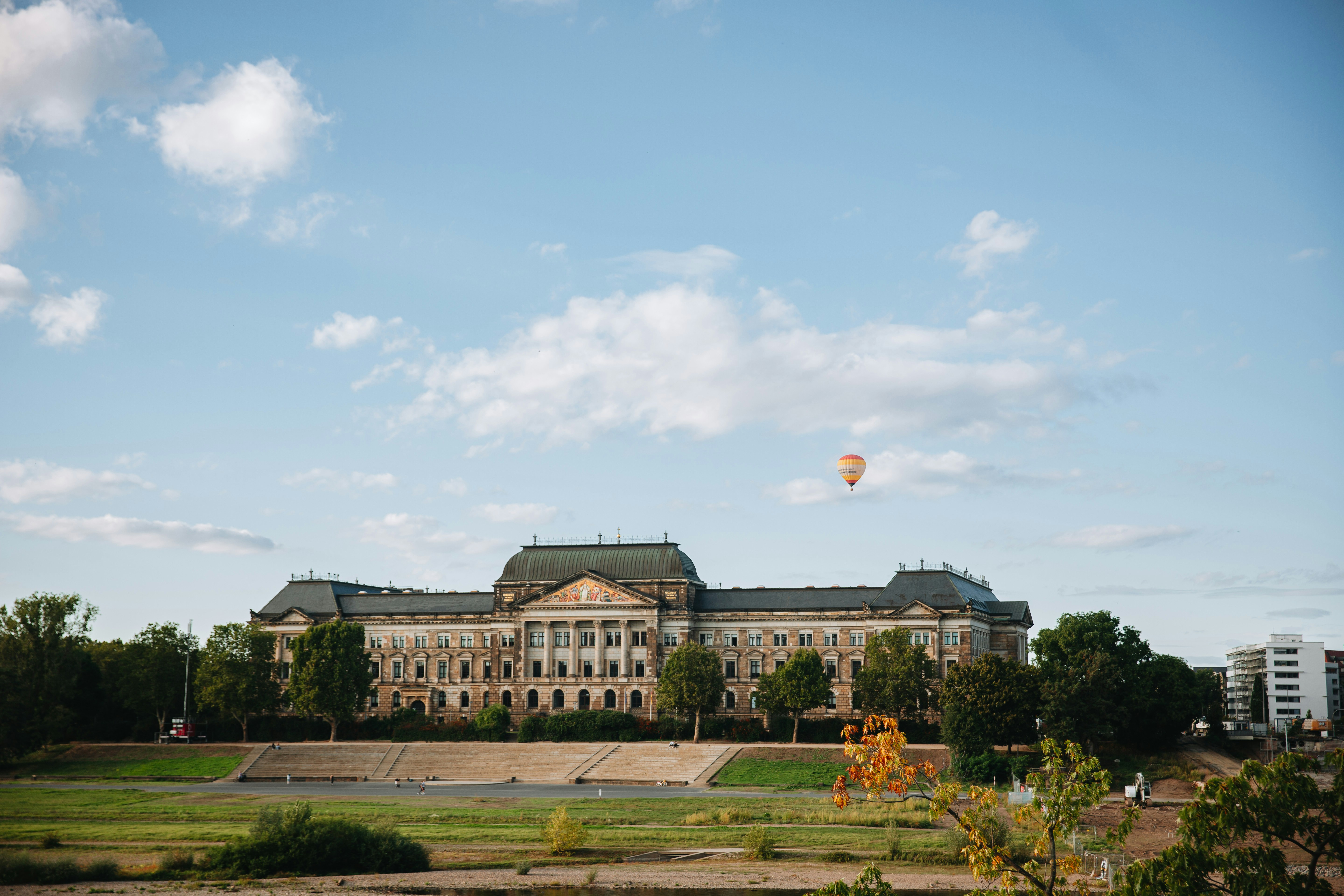 Grand building with trees and a hot air balloon.