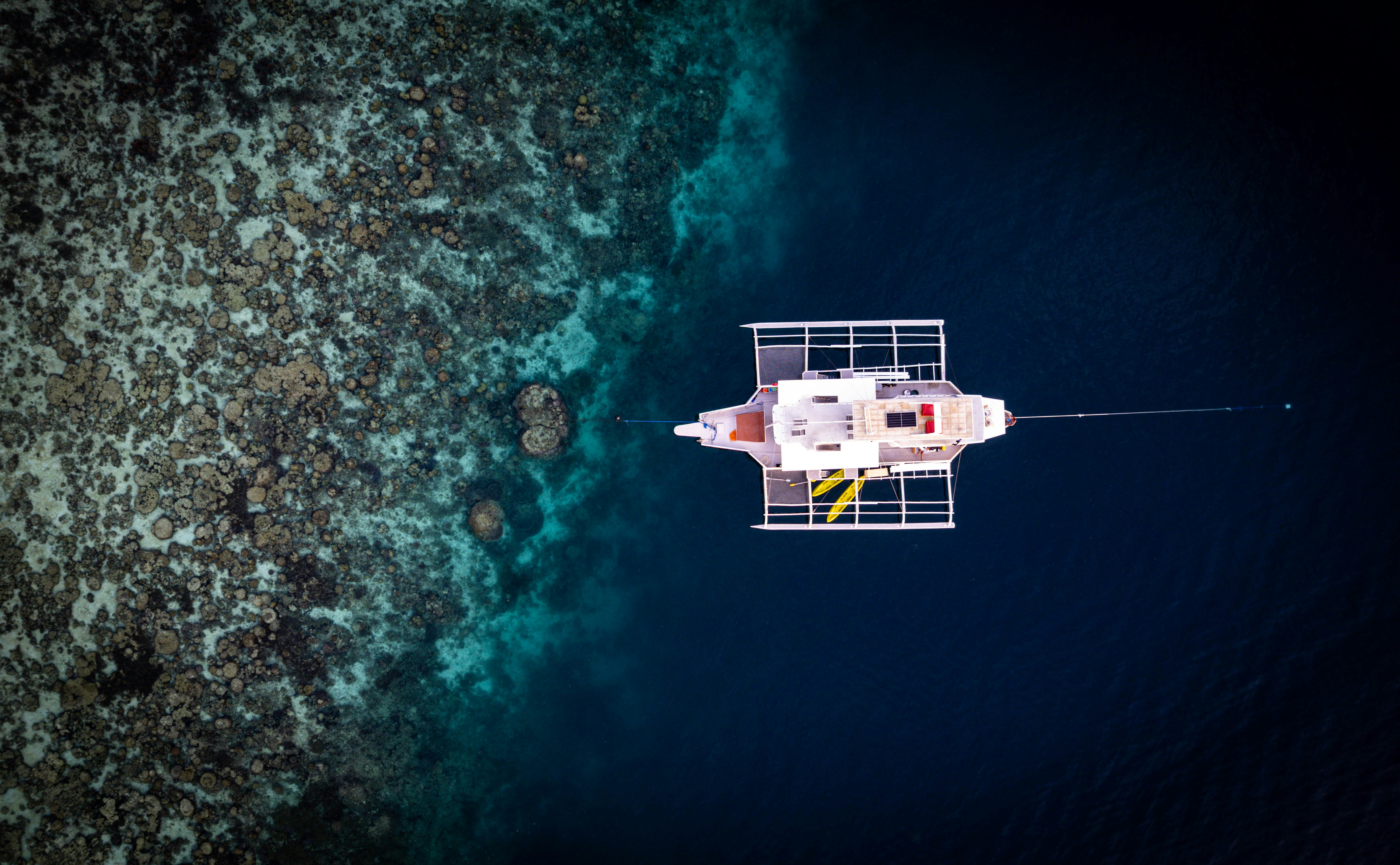 A boat floats over a coral reef in clear water.