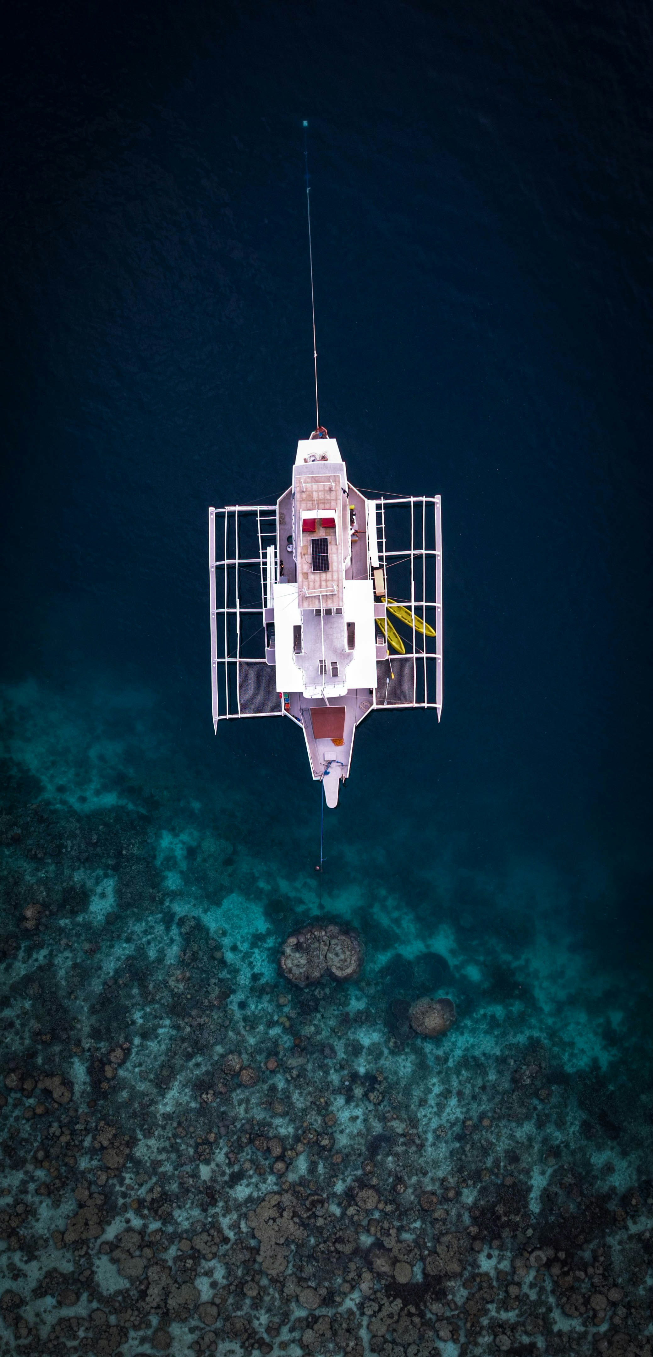 Top-Down Sentinel: A White Vessel Hovering Over a Turquoise Reef