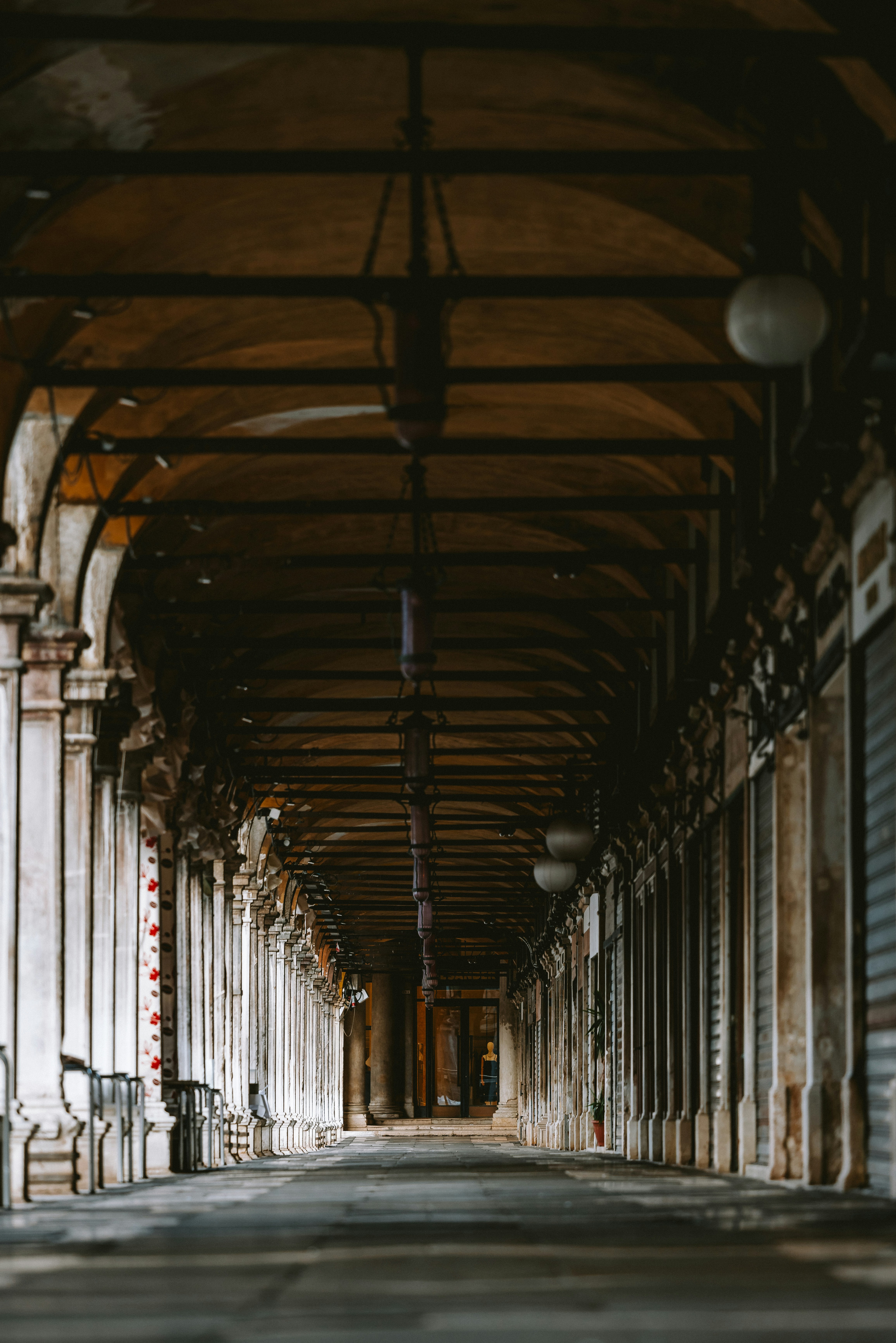Empty arched walkway with columns and hanging lights