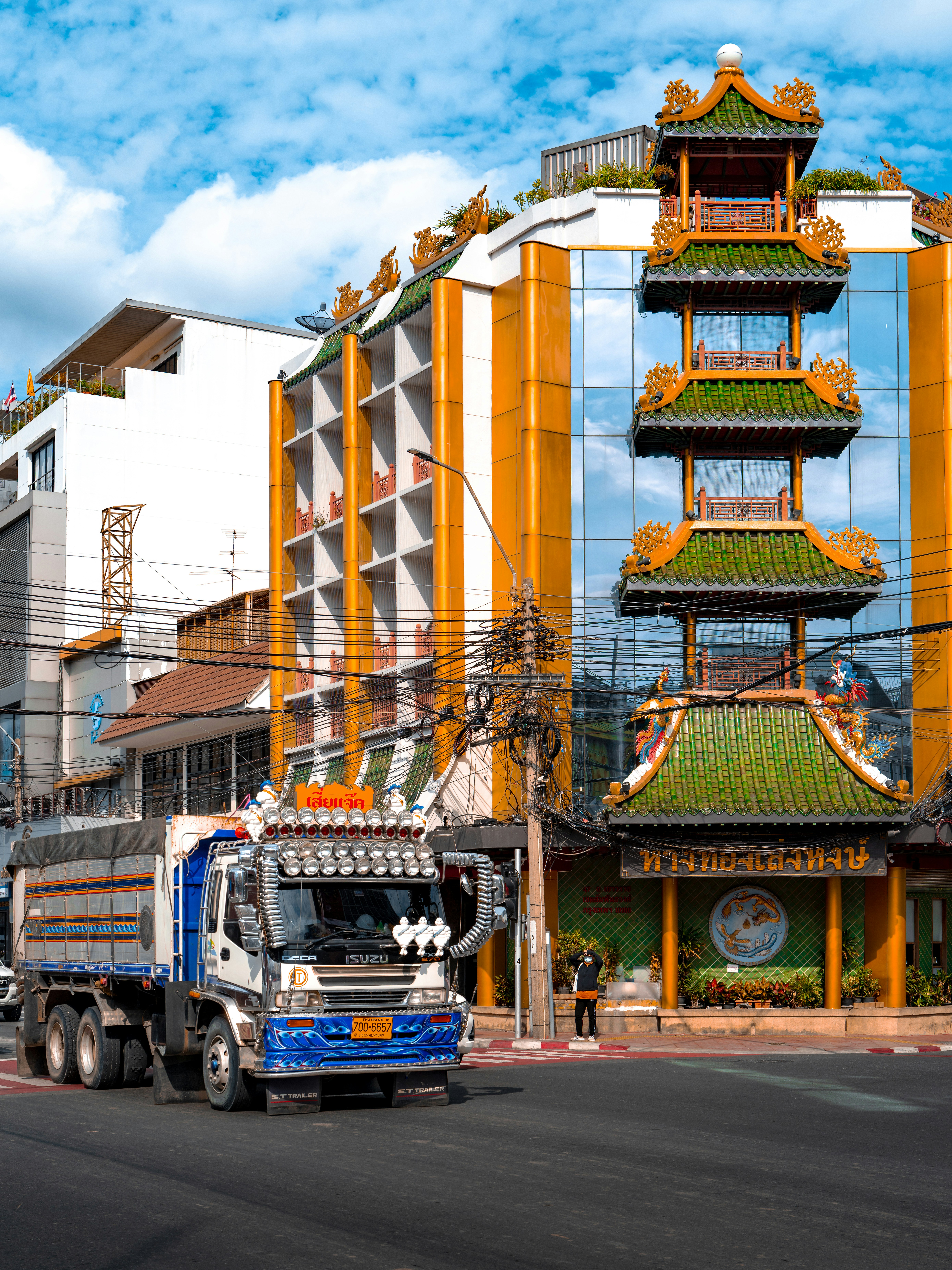A highly decorated truck | Truck passes ornate building with pagoda-style roof
