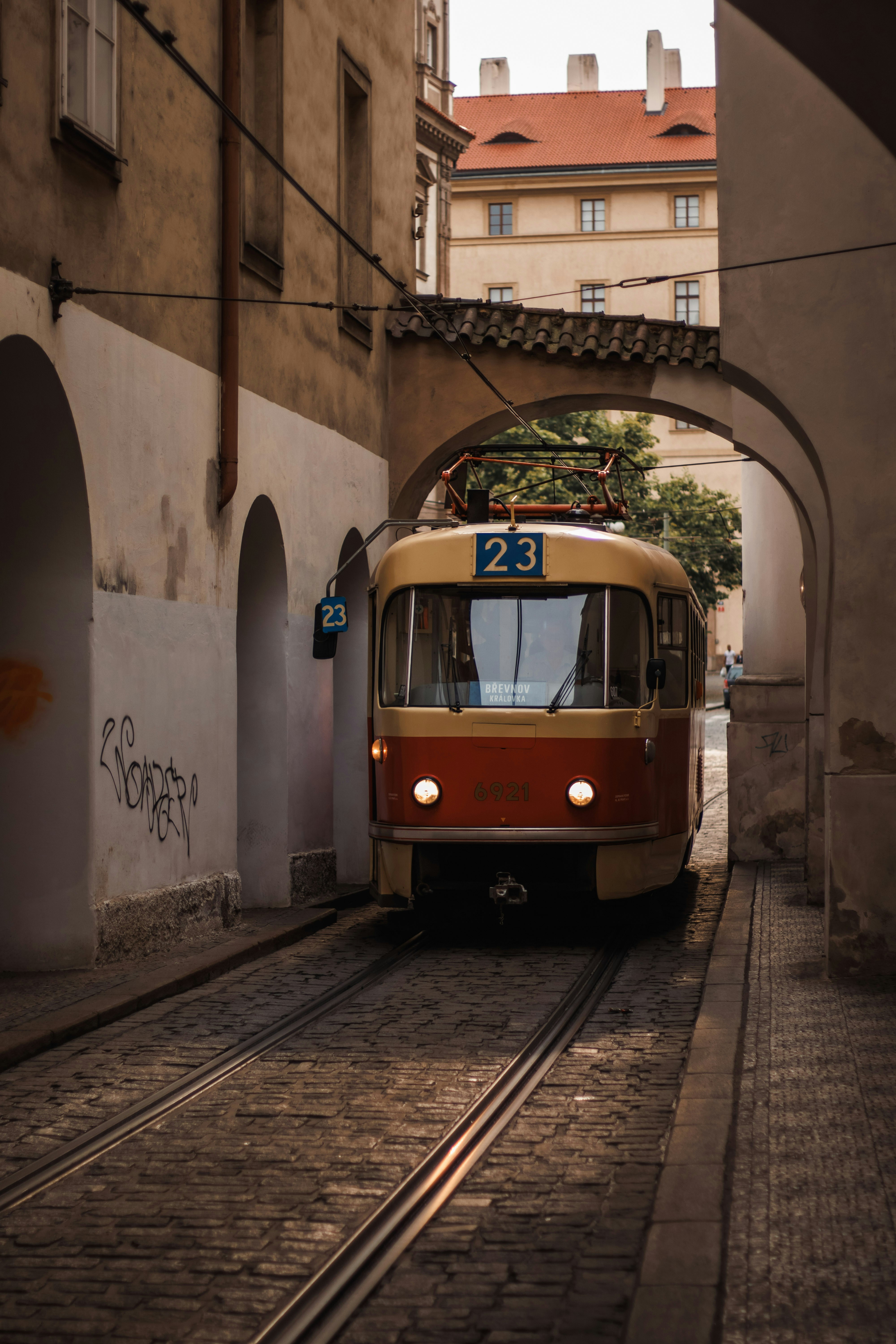 A vintage tram travels through a cobblestone street.