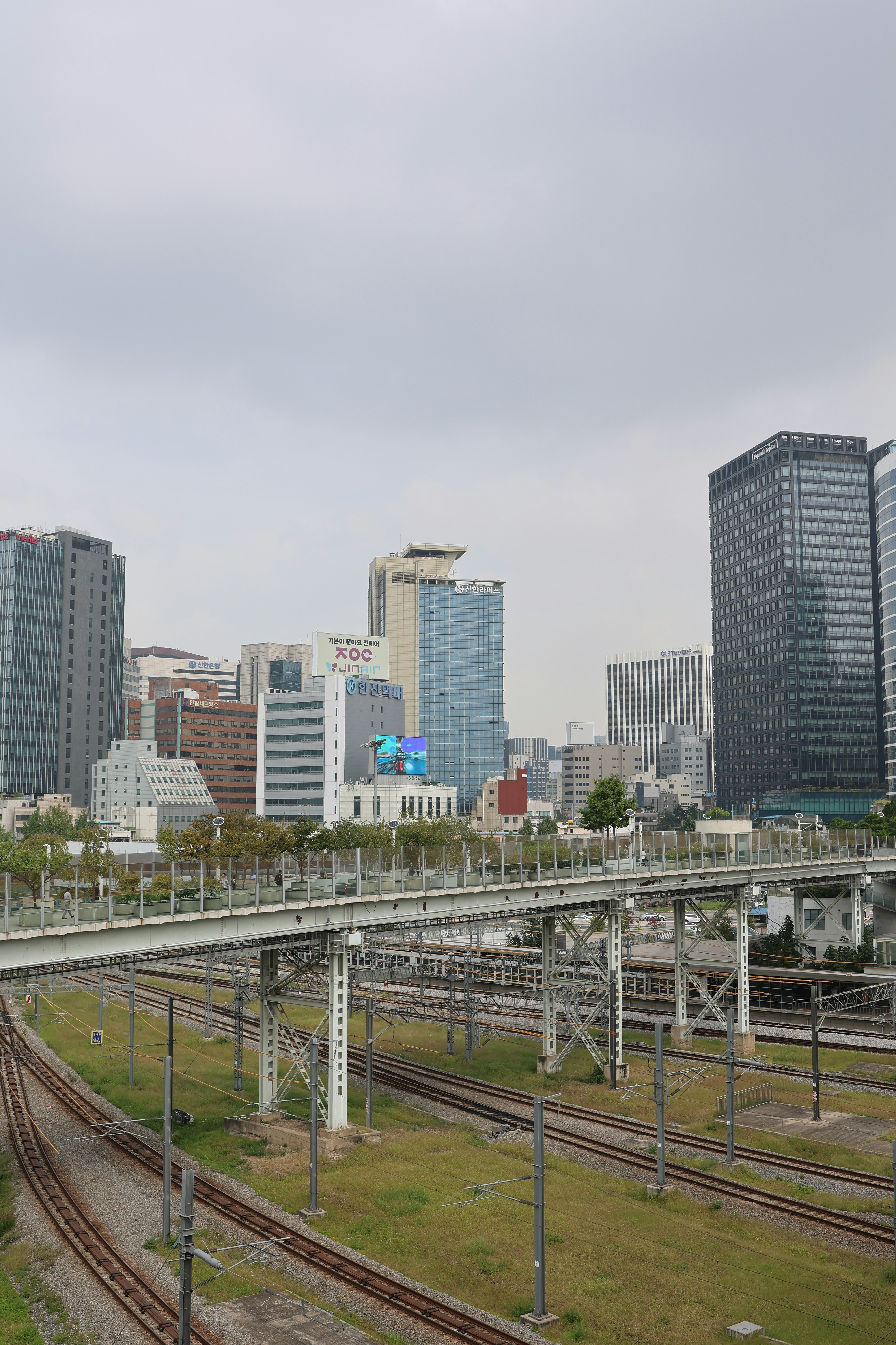 A sprawling cityscape featuring a blend of modern skyscrapers and railway infrastructure, highlighting urban development and connectivity.