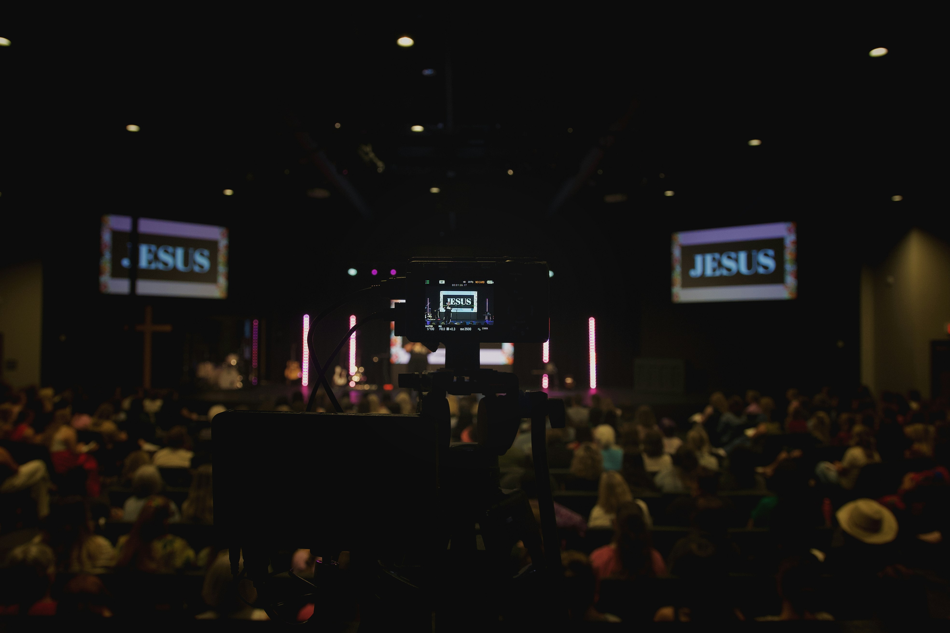 Who's in the house? (J.C) | Congregation watches screens displaying the word jesus.