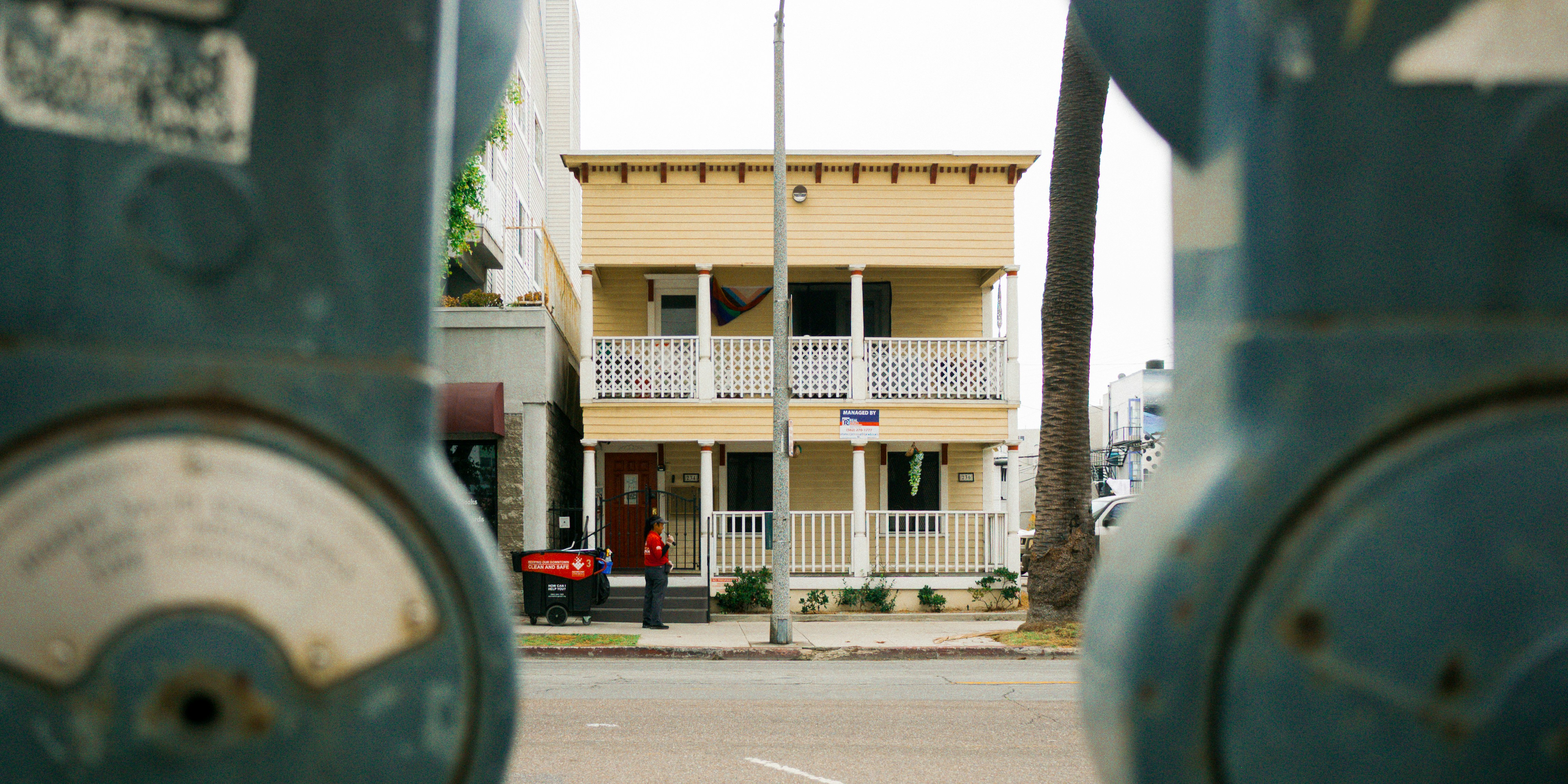 A charming yellow house framed by two vintage parking meters, showcasing a blend of urban life and residential warmth.