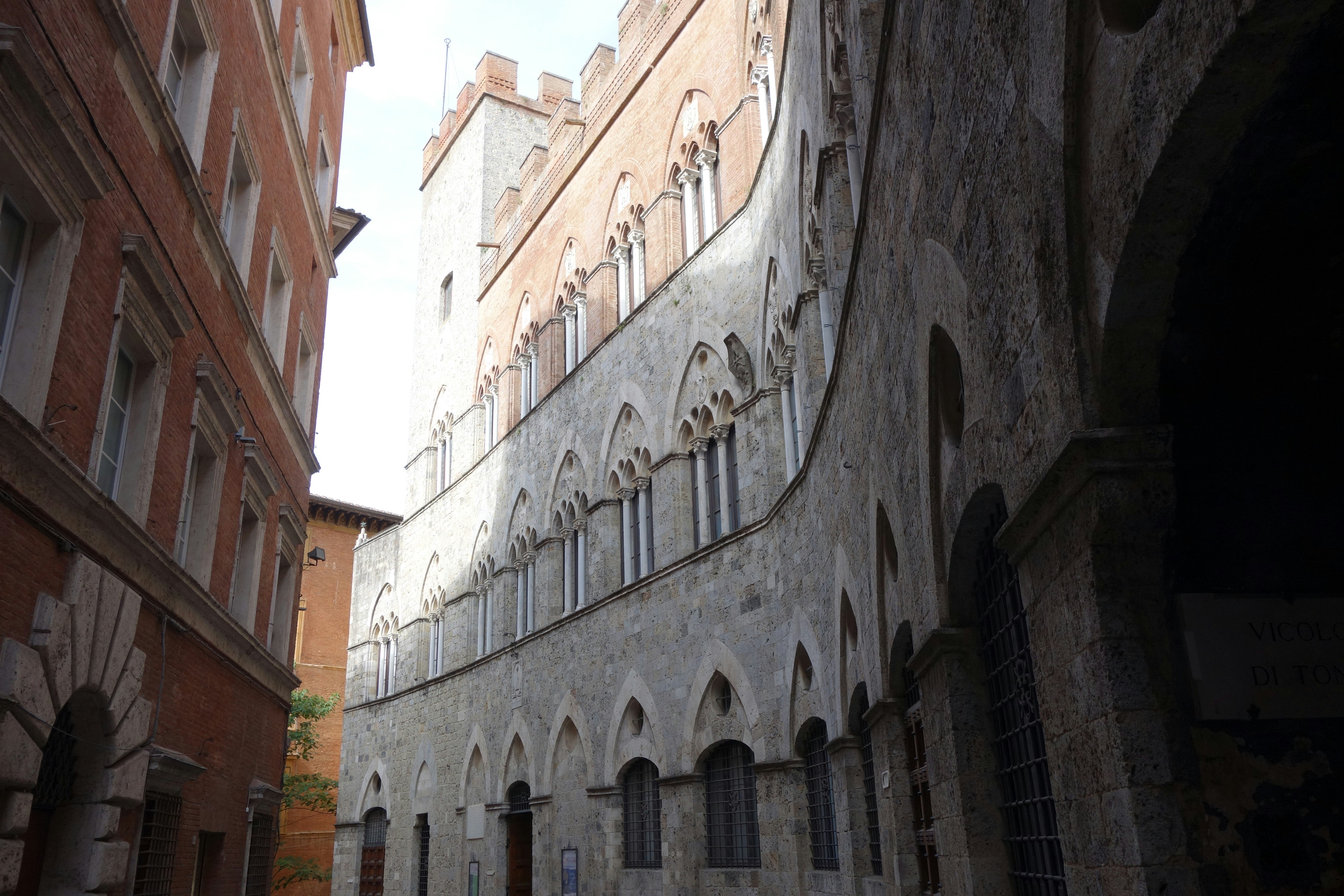 Arcade in shadowed stones: a narrow courtyard framed by weathered arches