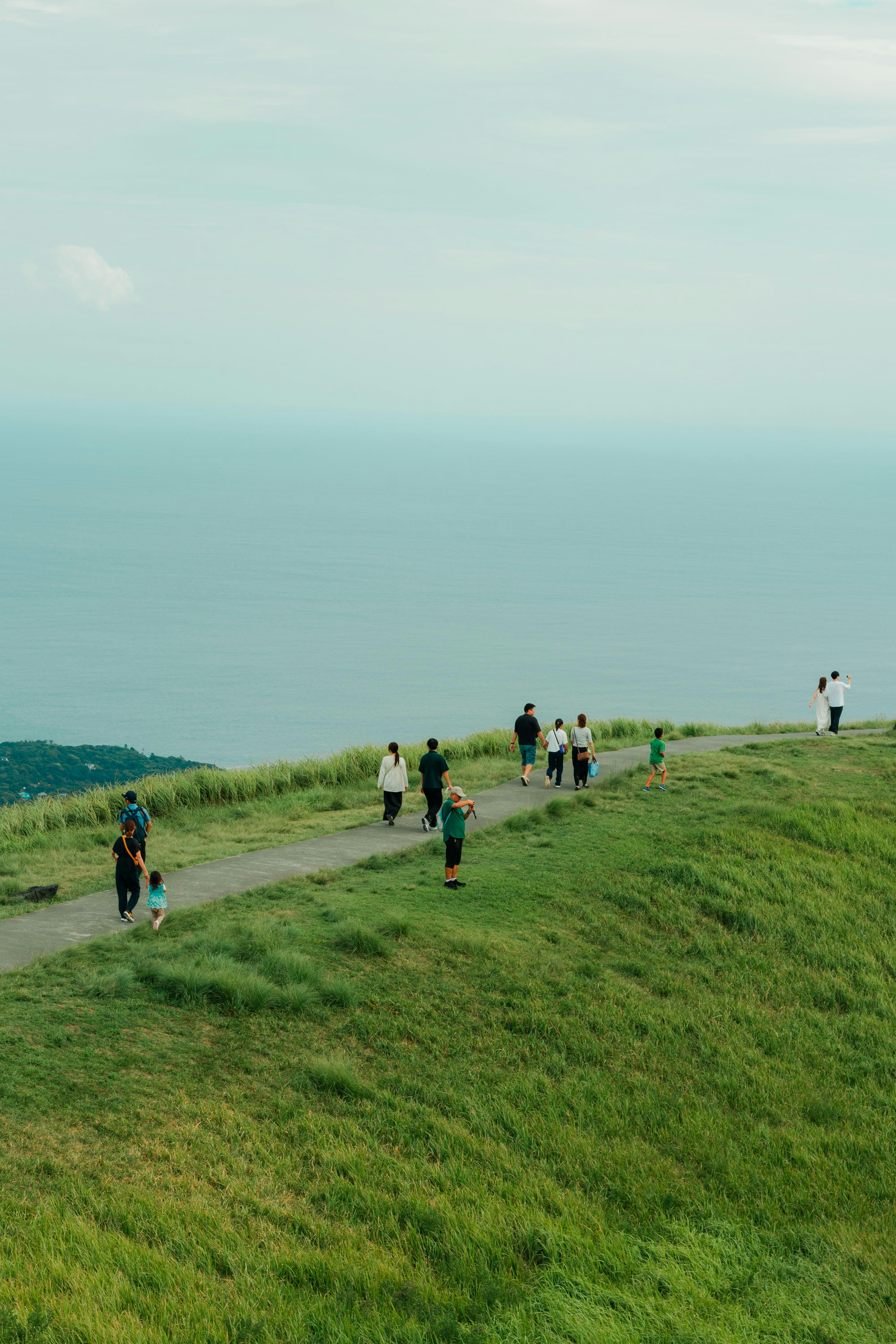 A Serene Climb: People Trek Along a Sea-View Cliff Path
