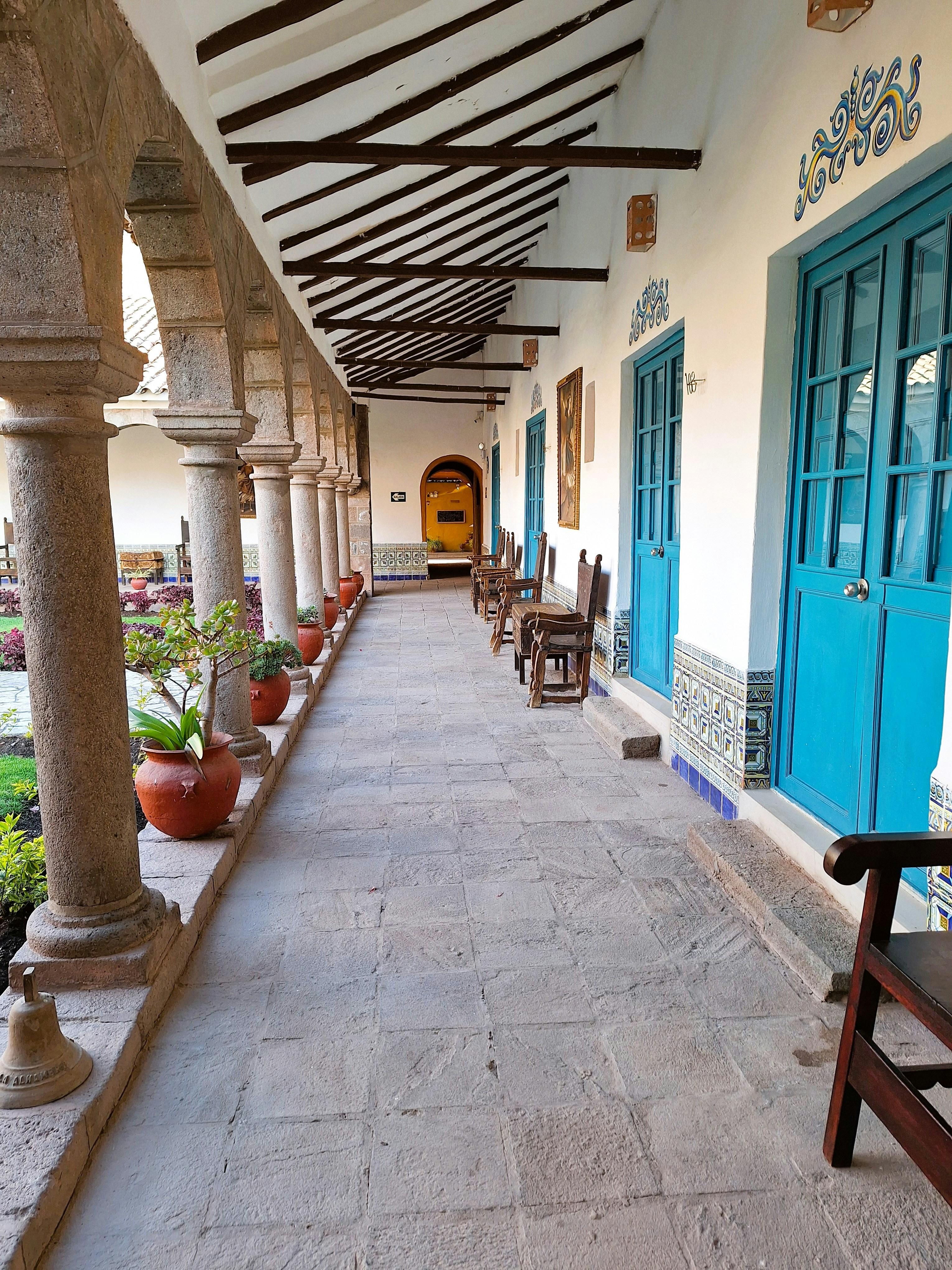 San Agustin Monasterio de la Recoleta, Urubamba, Sacred Valley, Peru | Courtyard walkway with stone columns and blue doors.