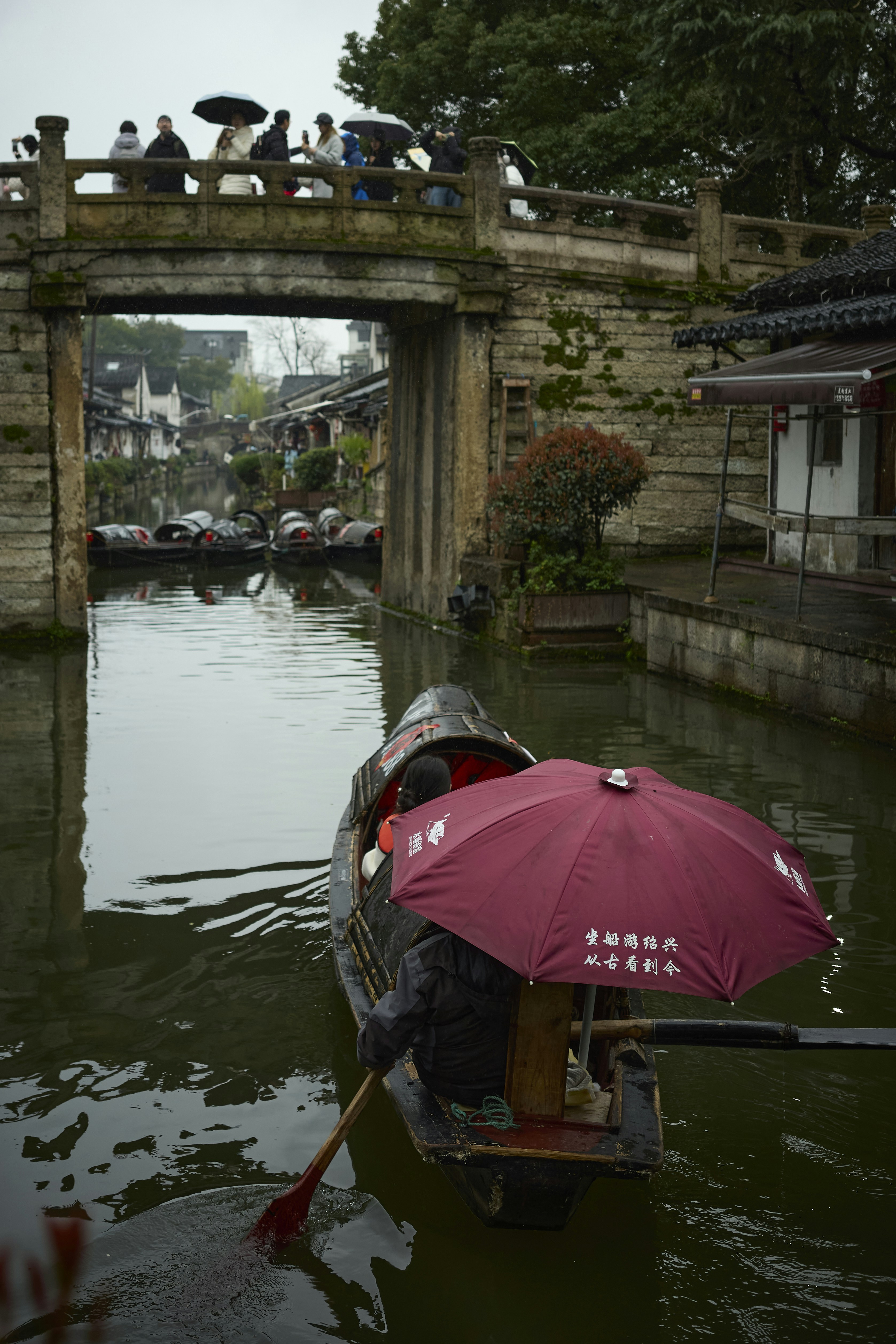 Boat on a canal passing under a stone bridge