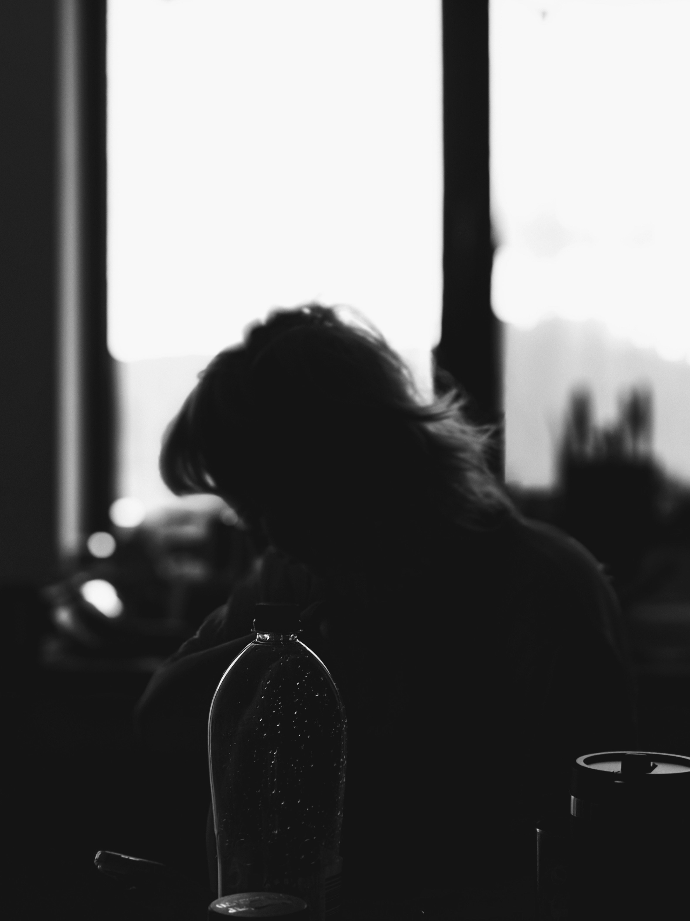 Silhouette of a person in a softly lit room, surrounded by objects, creating a mood of introspection.