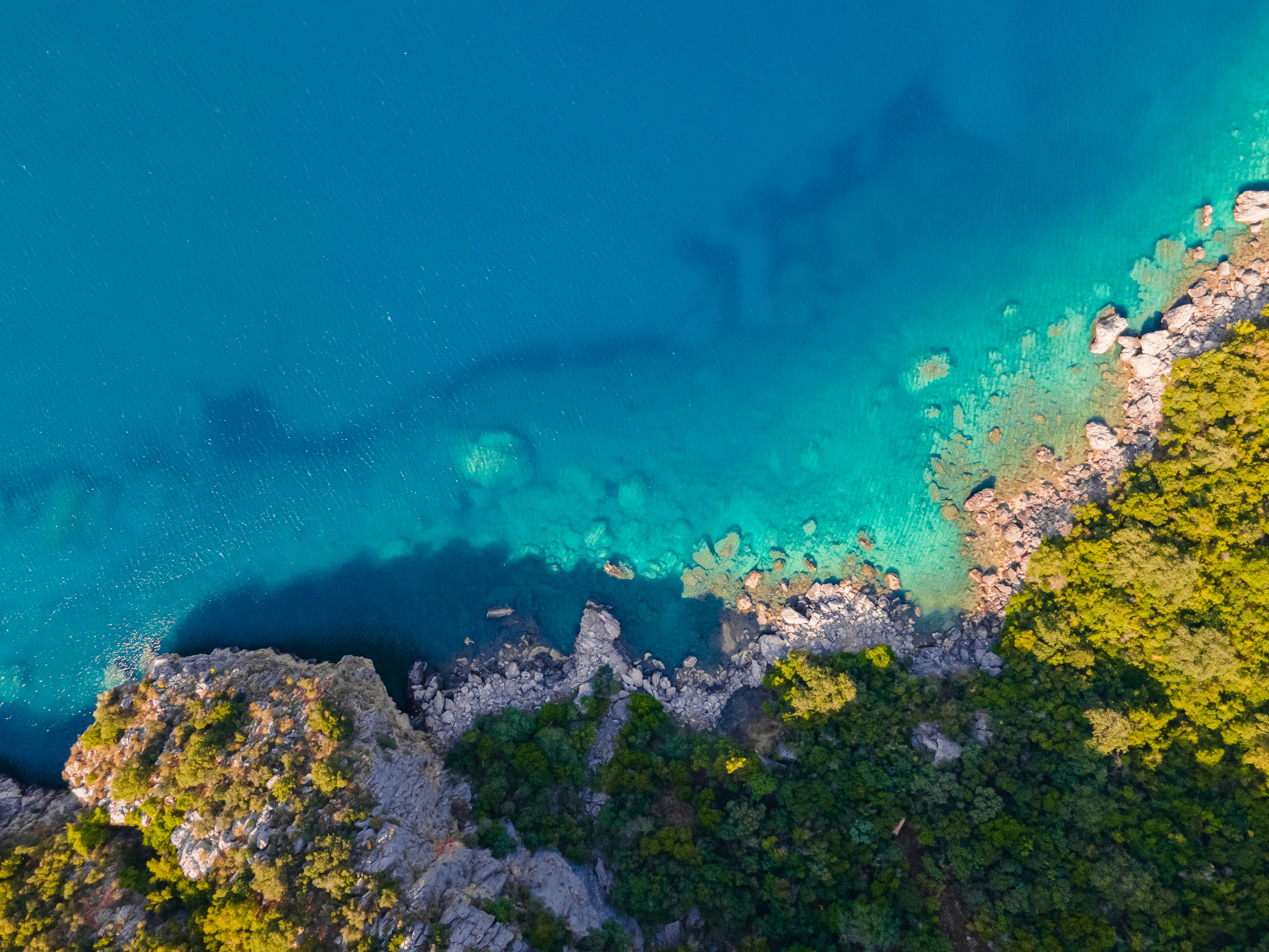 Aerial view of a rocky coastline with clear blue water.