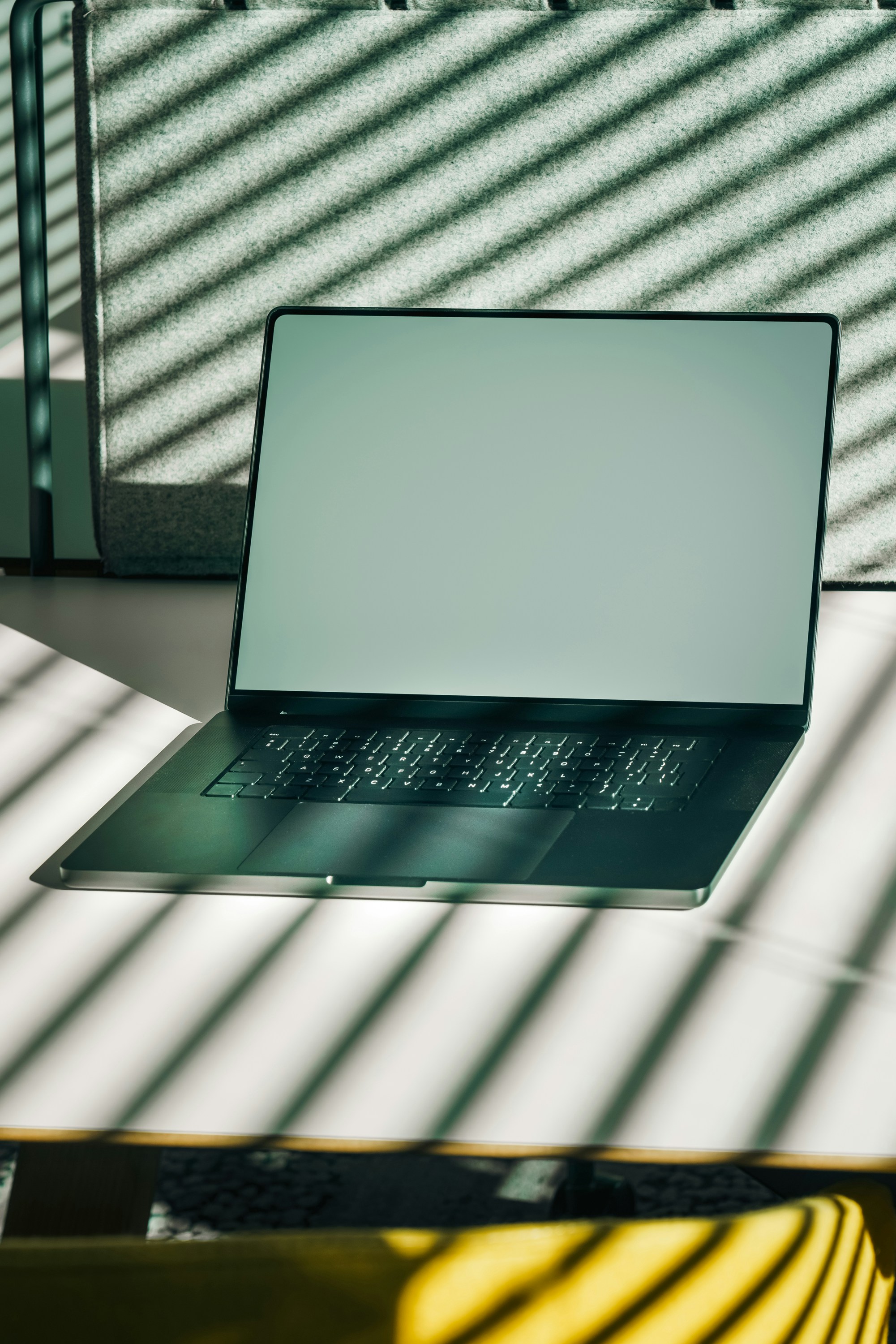 Laptop screen mockup office desk sunlight shadows. | Open laptop with blank screen on a desk.
