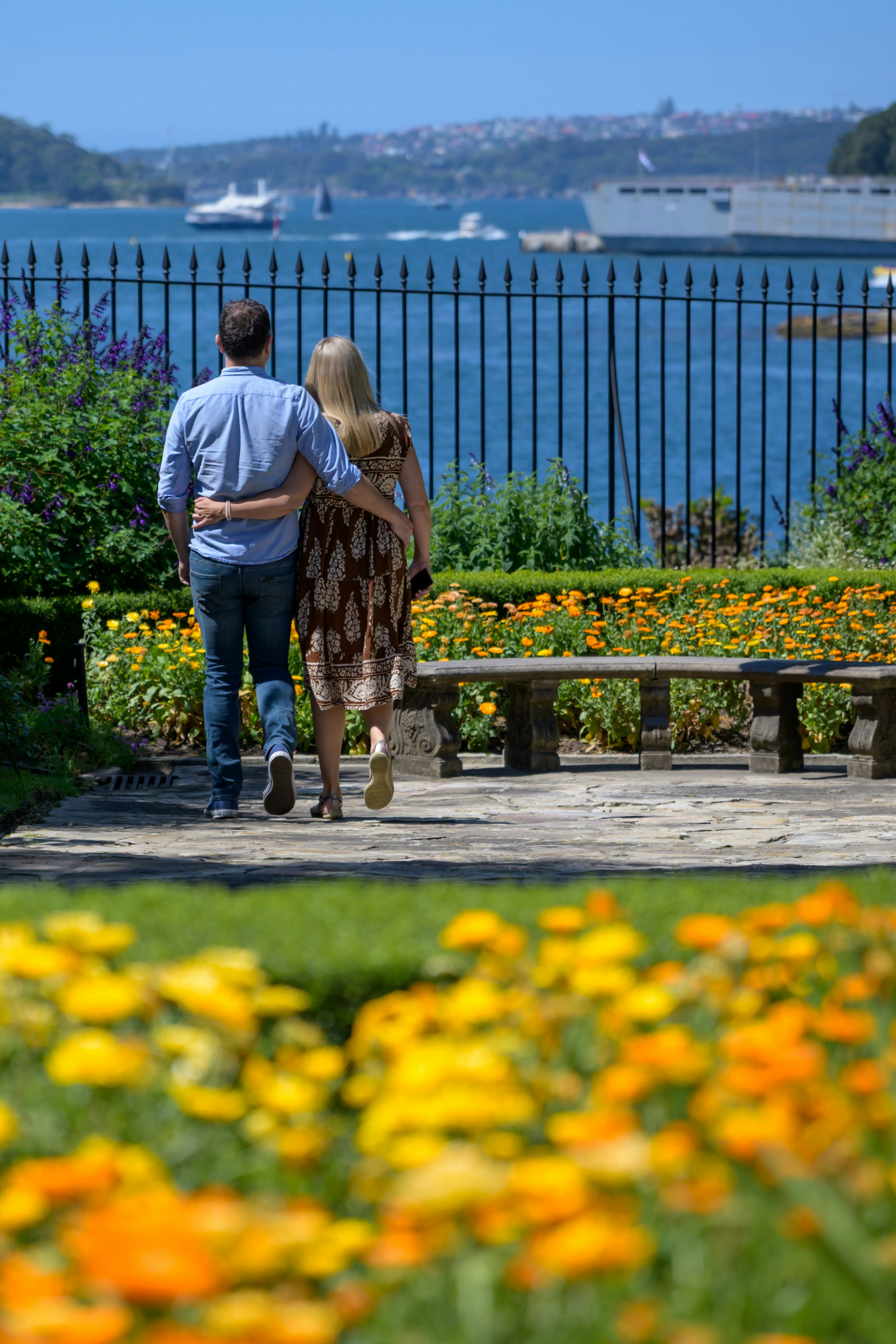 Couple walking in garden overlooking harbor with boats
