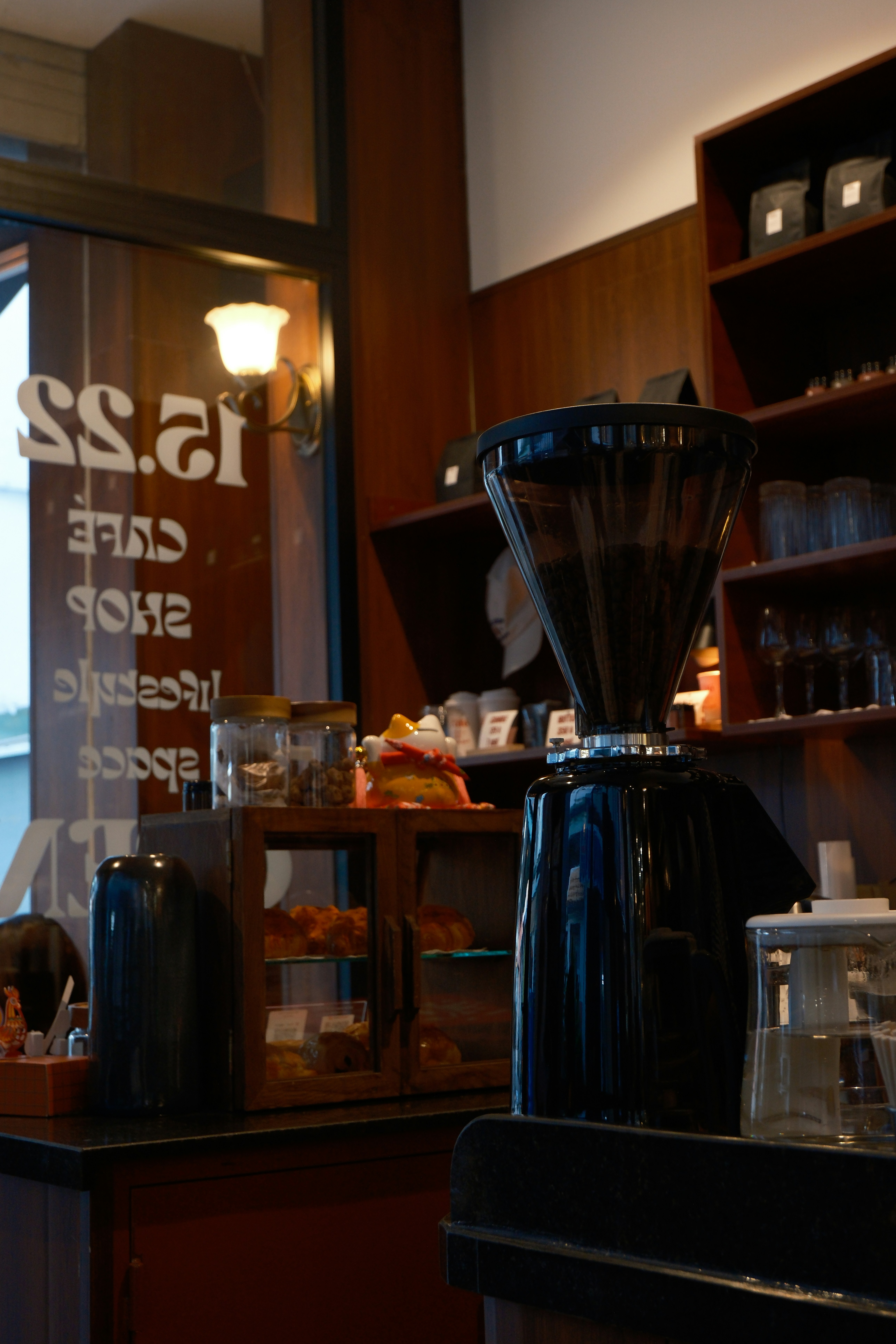 Coffee grinder in a cafe with pastries on display.