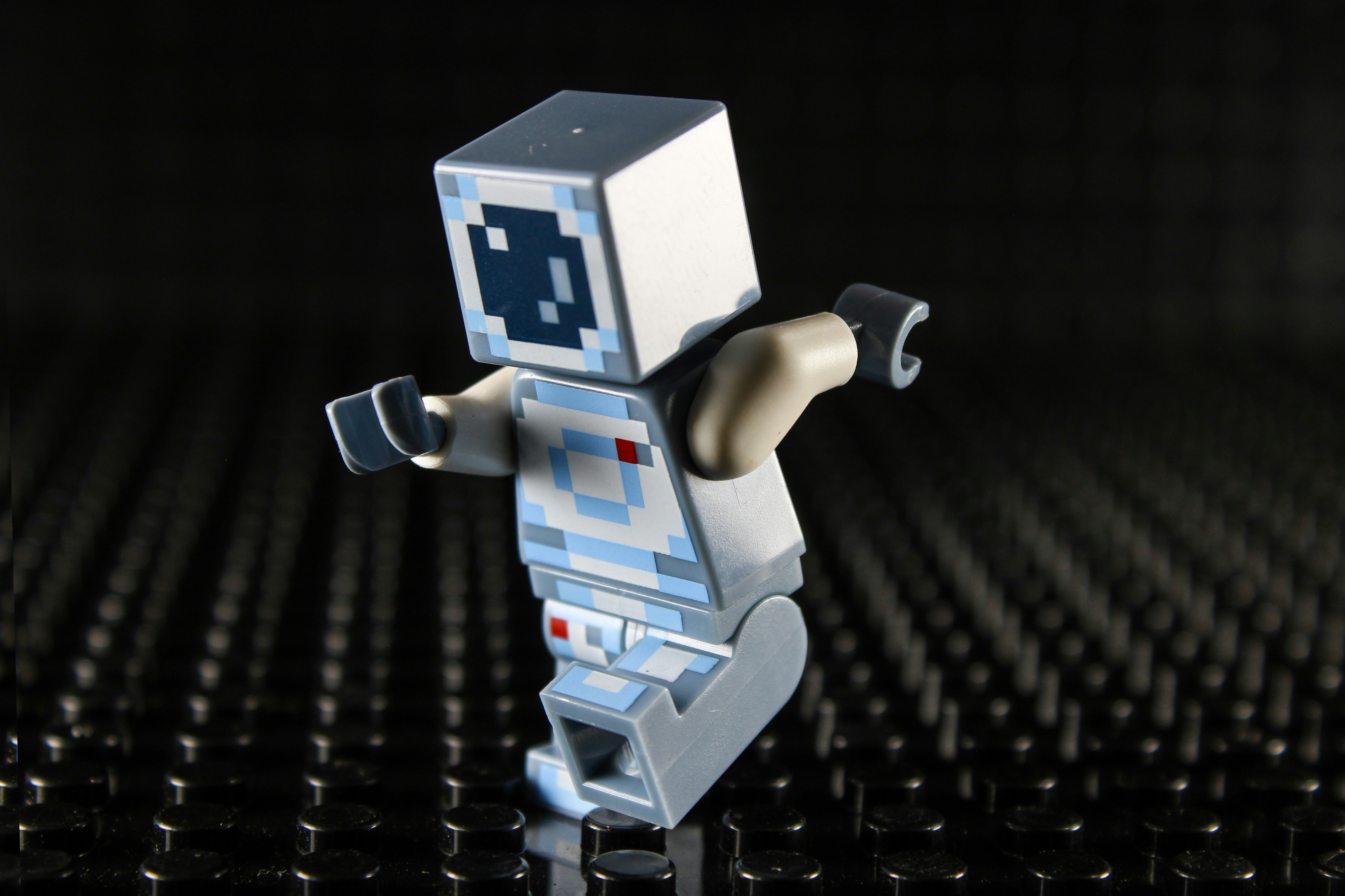 A whimsical blue and white robot figure in mid-stride, set against a glossy black background that enhances its vibrant colors.