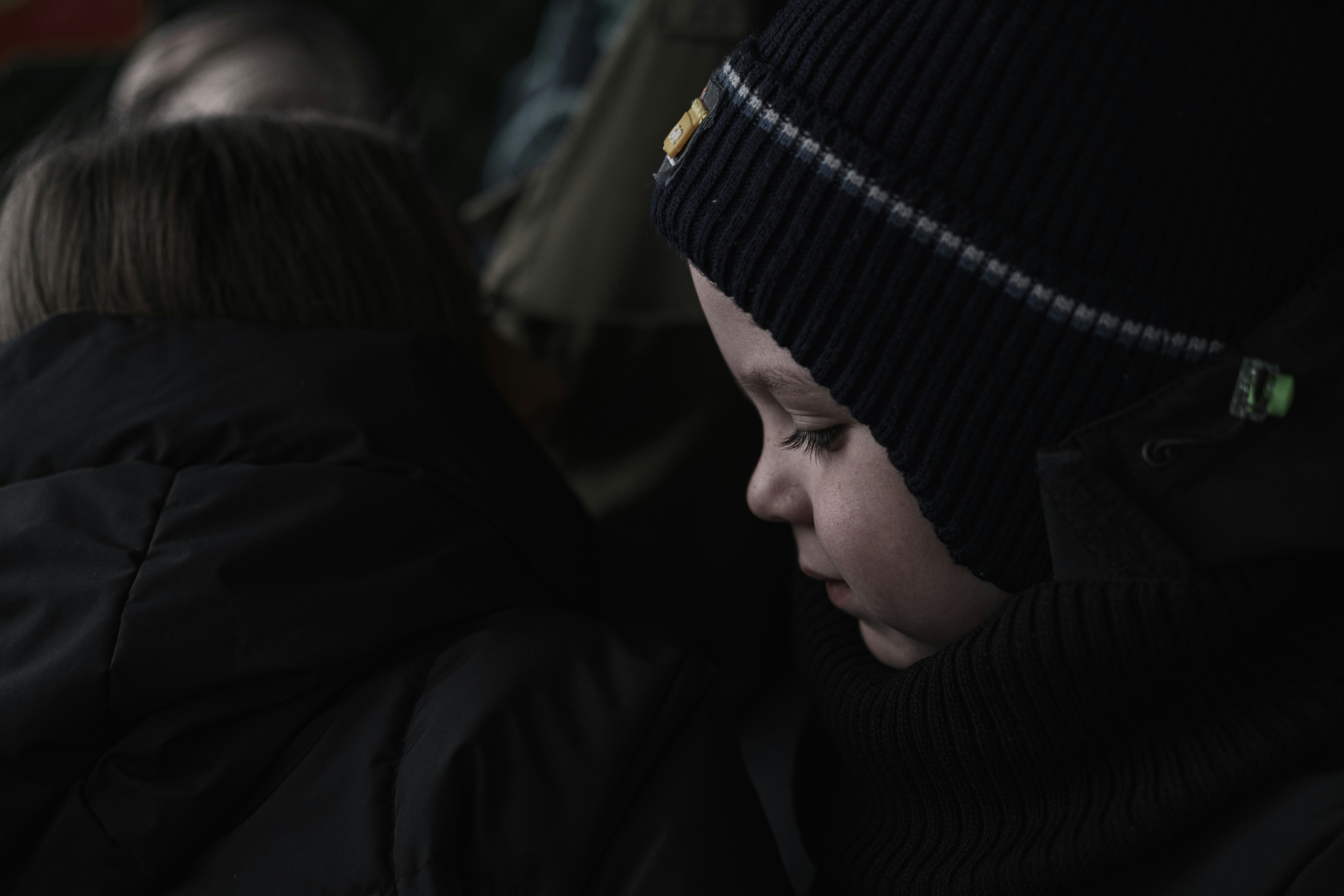 Young boy in a beanie looking down thoughtfully