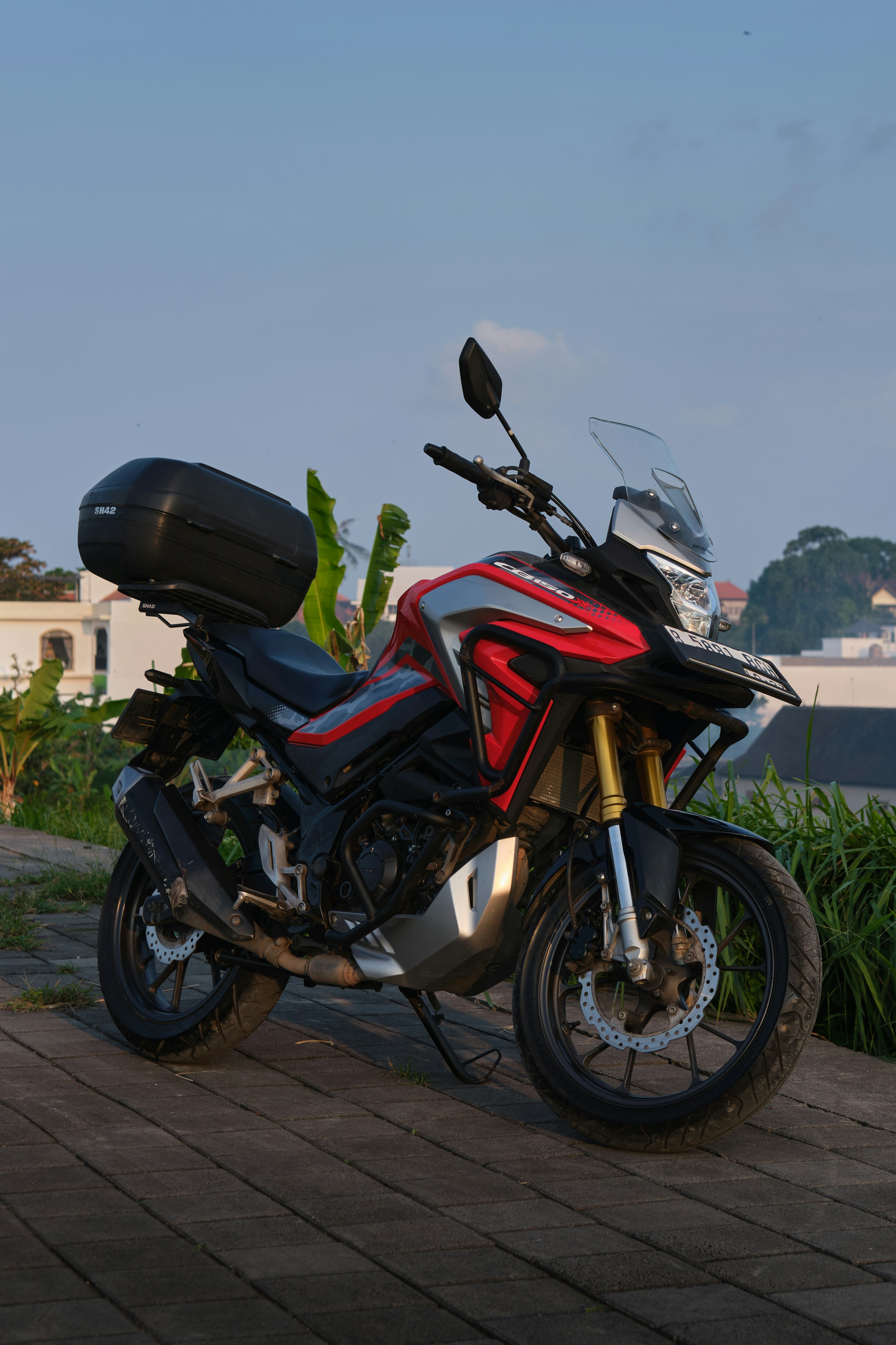 A sleek motorcycle parked on a stone pathway, surrounded by lush greenery, ready for the next adventure.