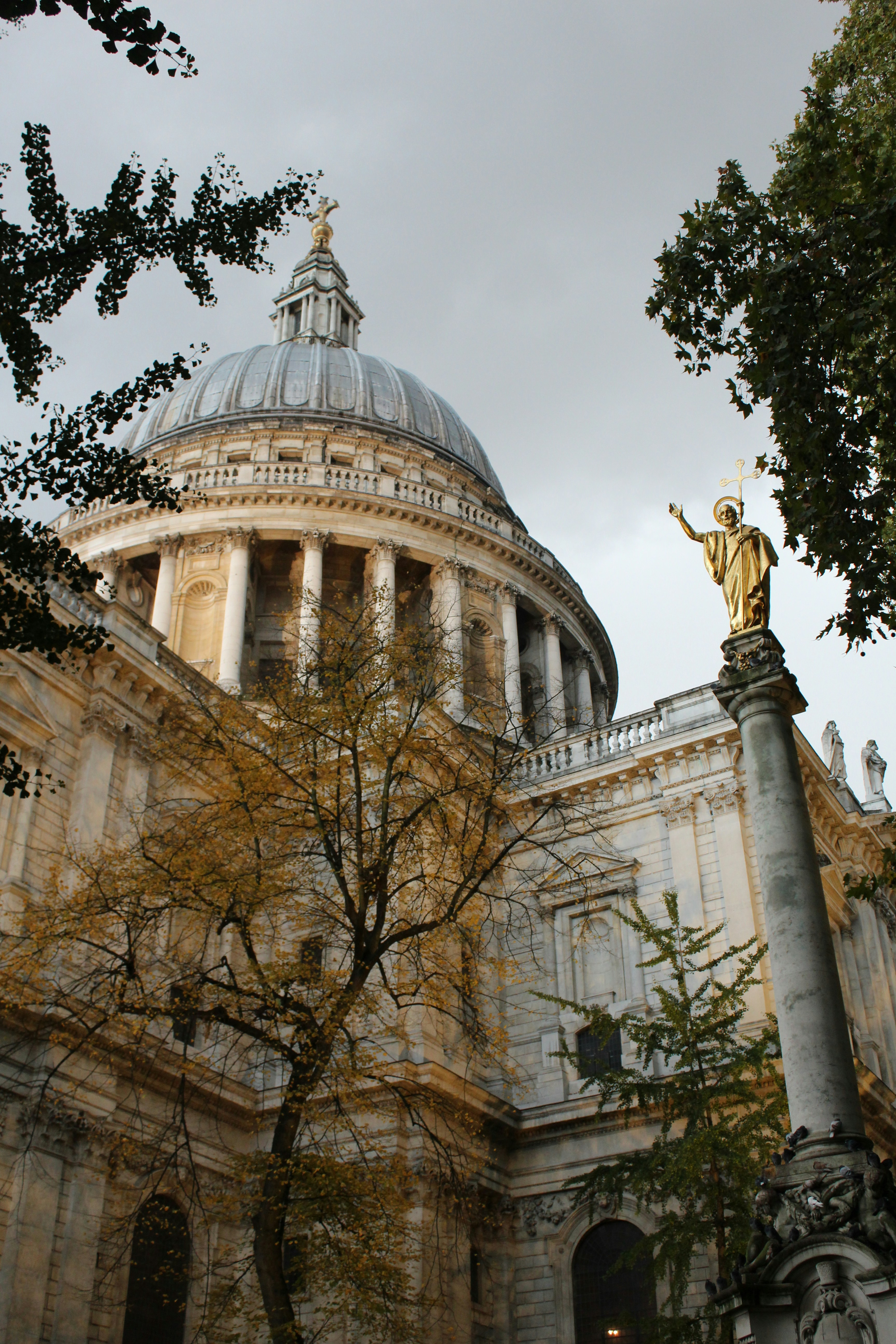 A majestic dome crowned with a golden figure stands amid autumn foliage, capturing a moment of architectural grandeur.