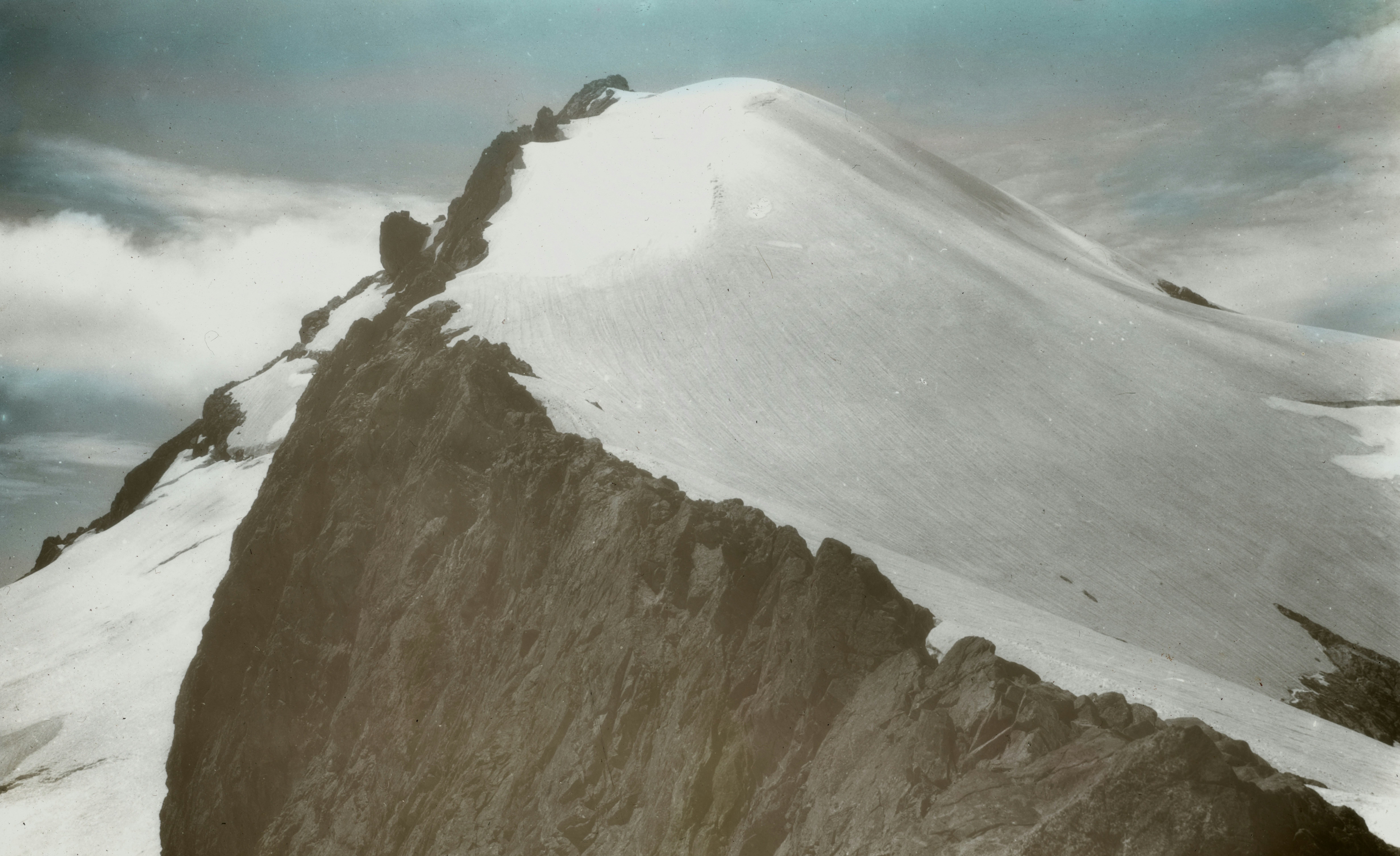 Jagged mountain ridge adorned with snow under a dramatic sky, showcasing the raw beauty of nature's architecture.