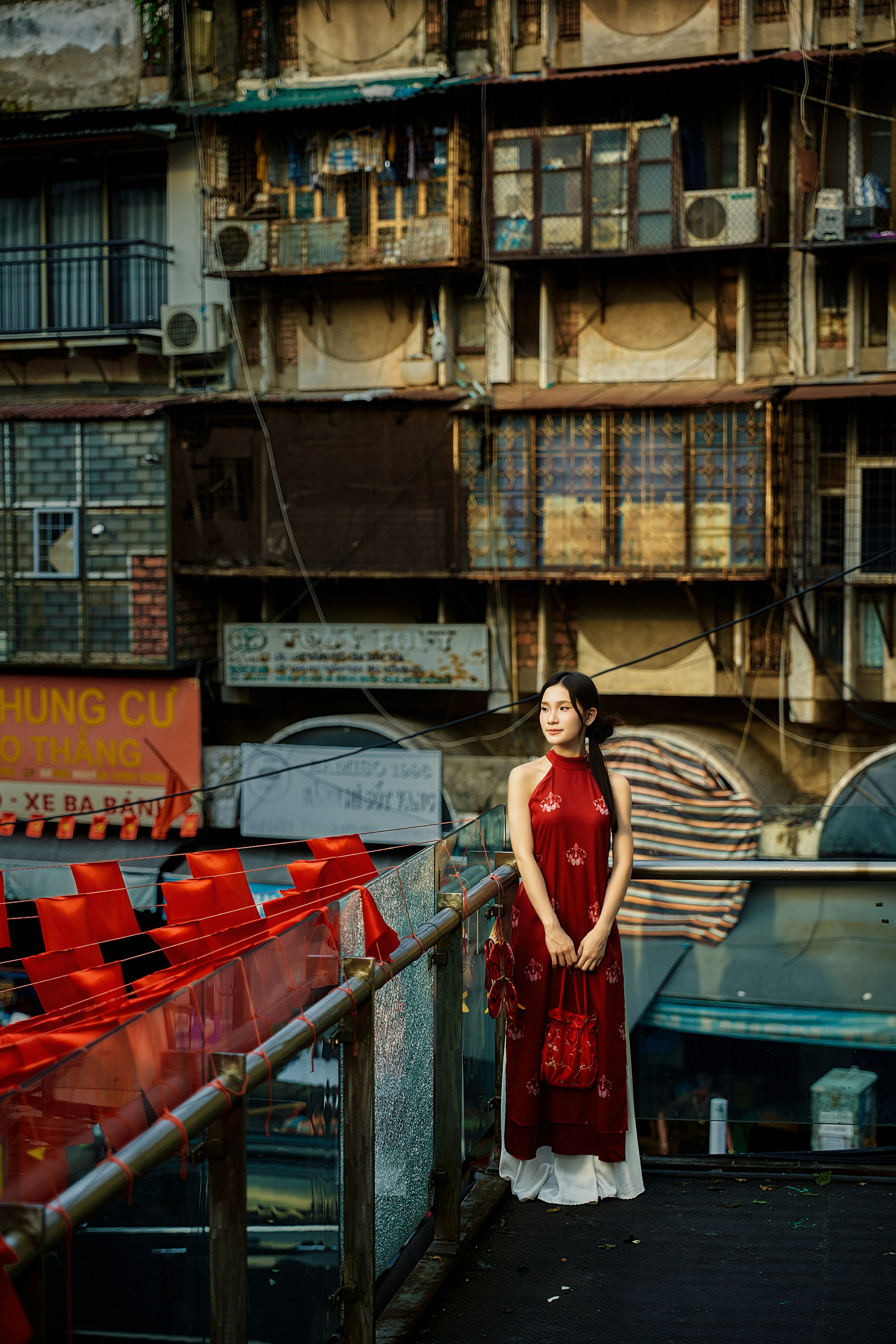 Scarlet on the Rail: A Poised Figure Amid Weathered Balconies