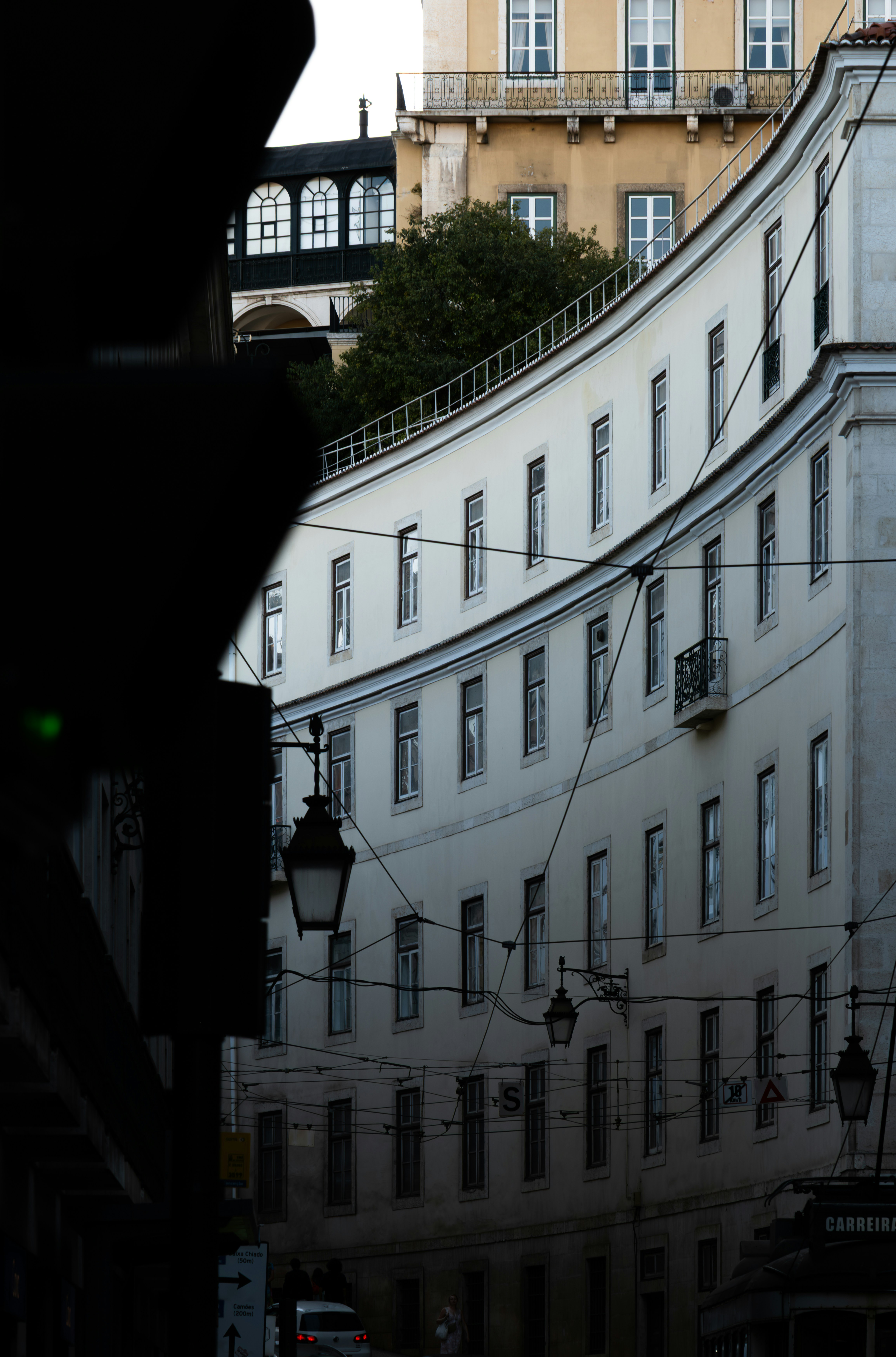 Architectural silhouette showcasing a curved street framed by buildings, with intricate details of street lamps and balconies. 