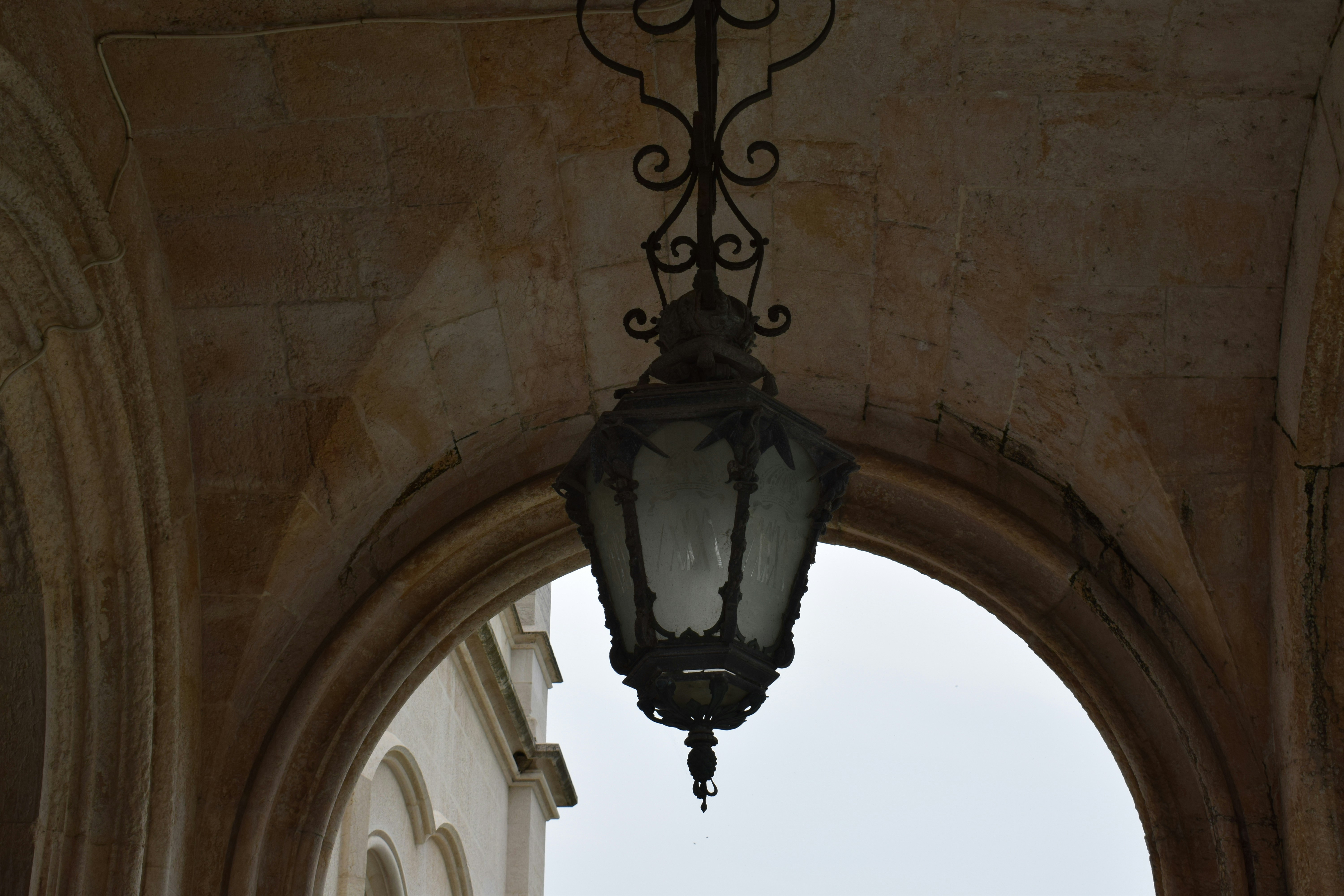 Old lantern in Miramare castle in Italy. | Ornate lantern hanging in arched walkway