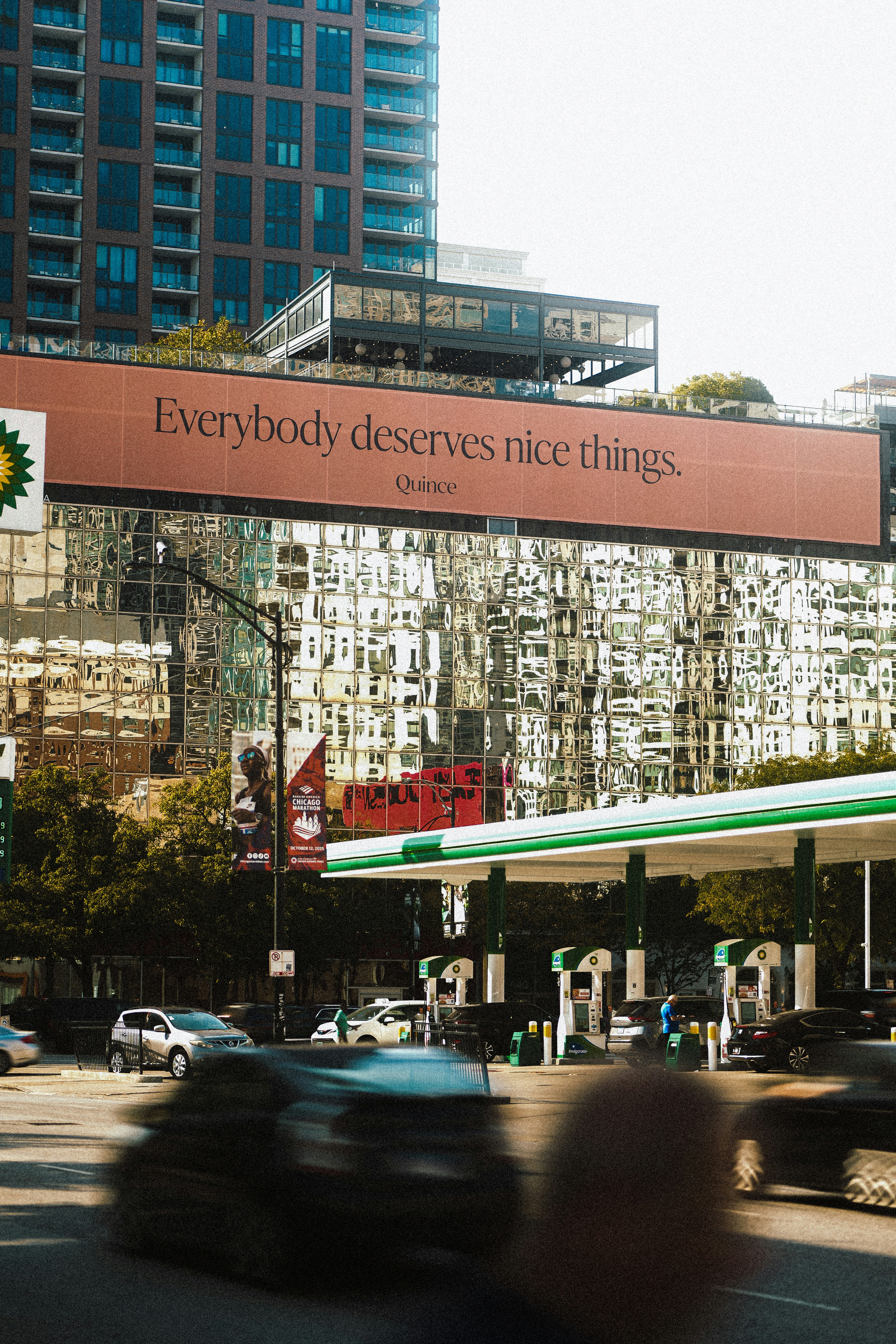 Billboard displaying the phrase 'Everybody deserves nice things.' against a backdrop of reflective buildings and bustling traffic.