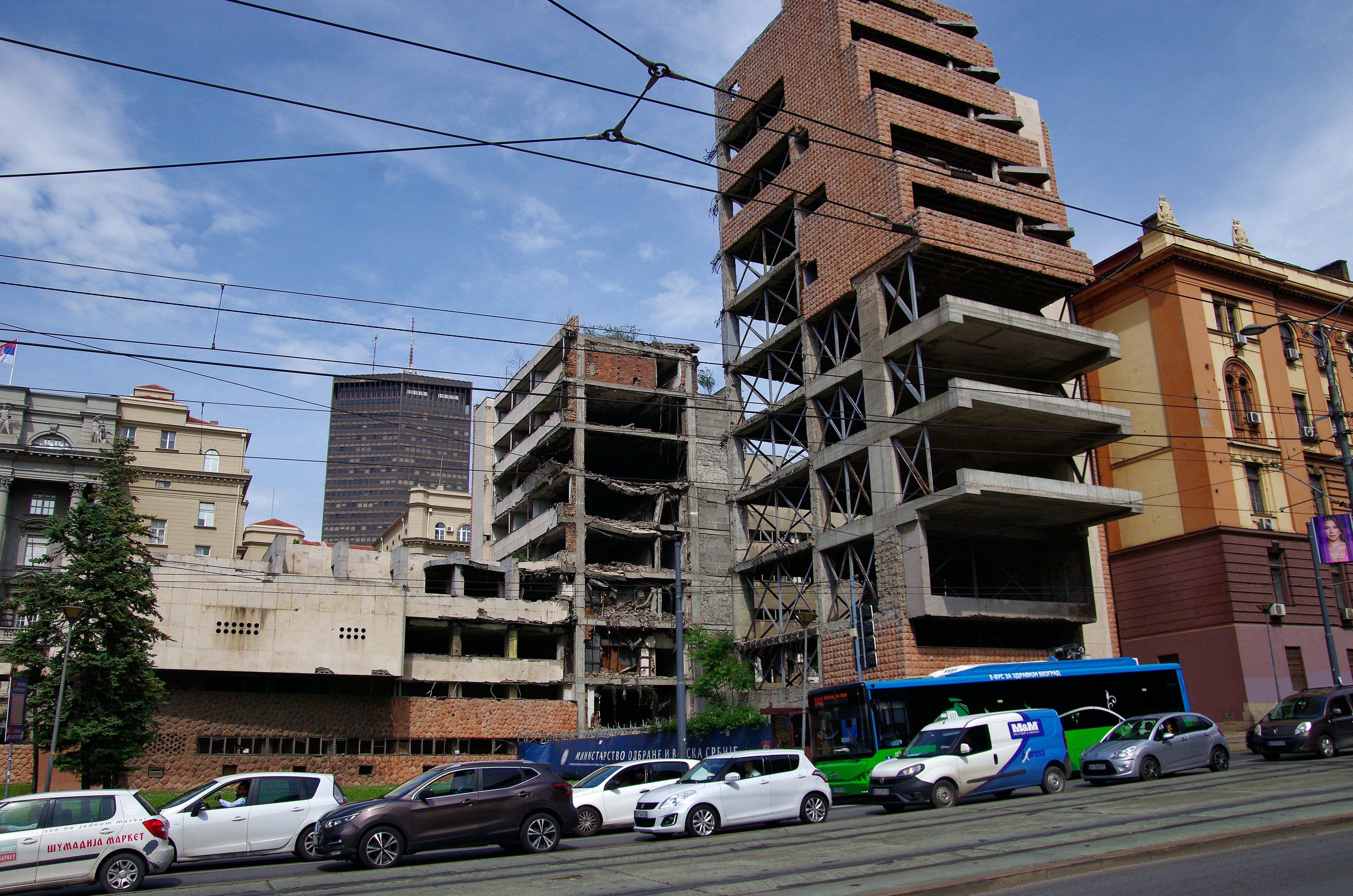 A partially demolished building stands alongside modern structures in an urban setting, showcasing the contrast between old and new architecture.