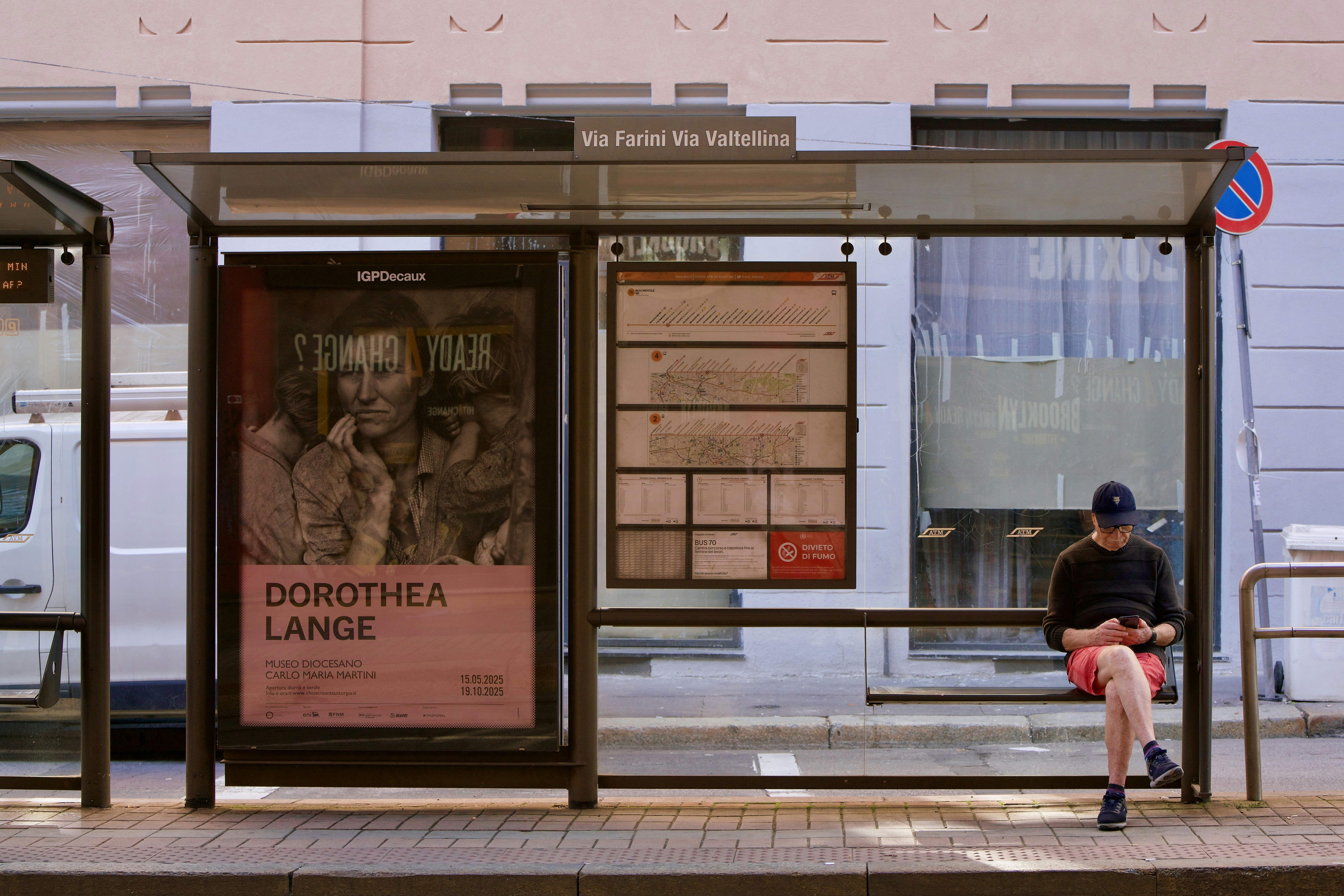 Woman sitting at bus stop checking phone
