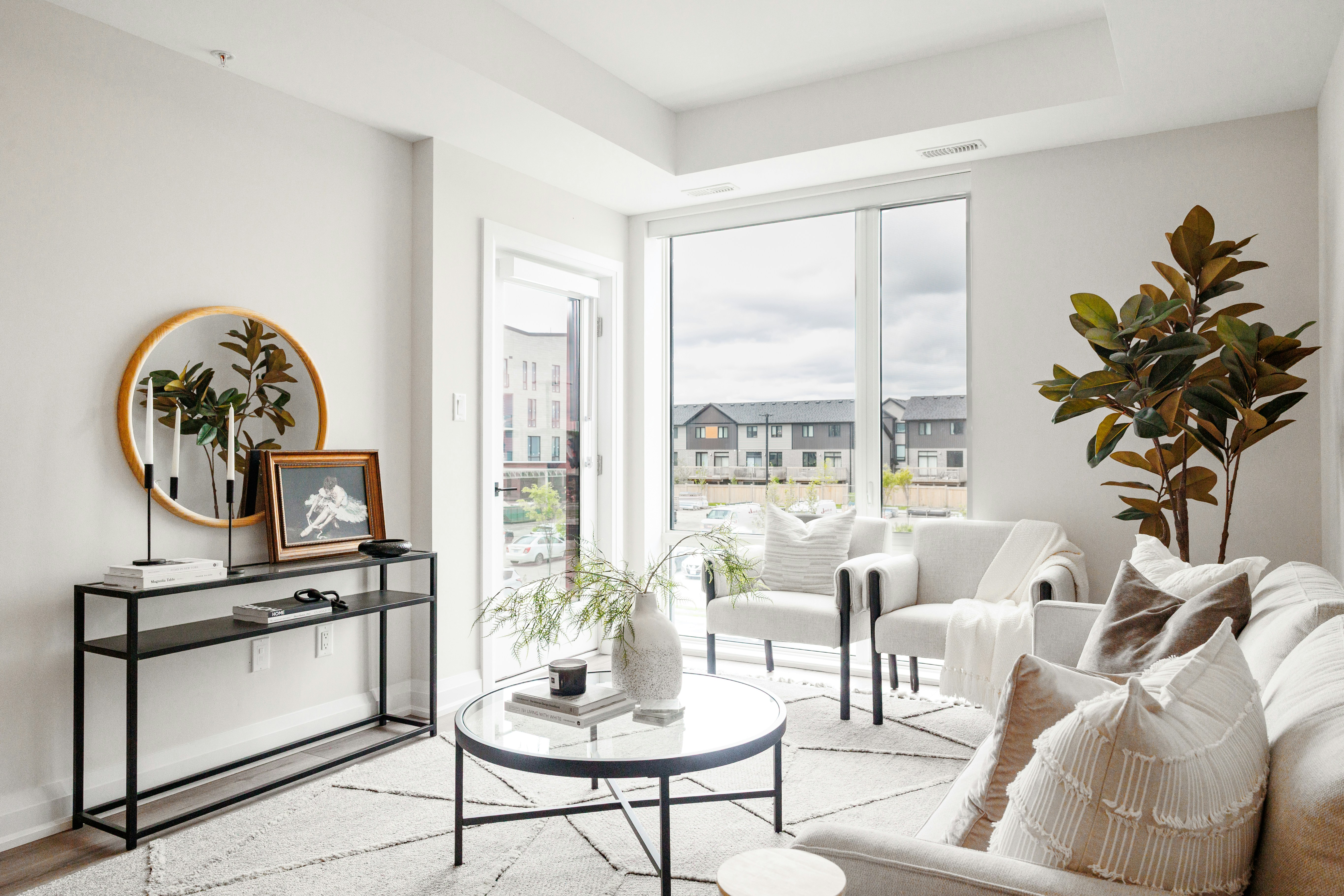Bright and airy living room featuring a stylish coffee table, contemporary furniture, and a large window showcasing an outdoor view.