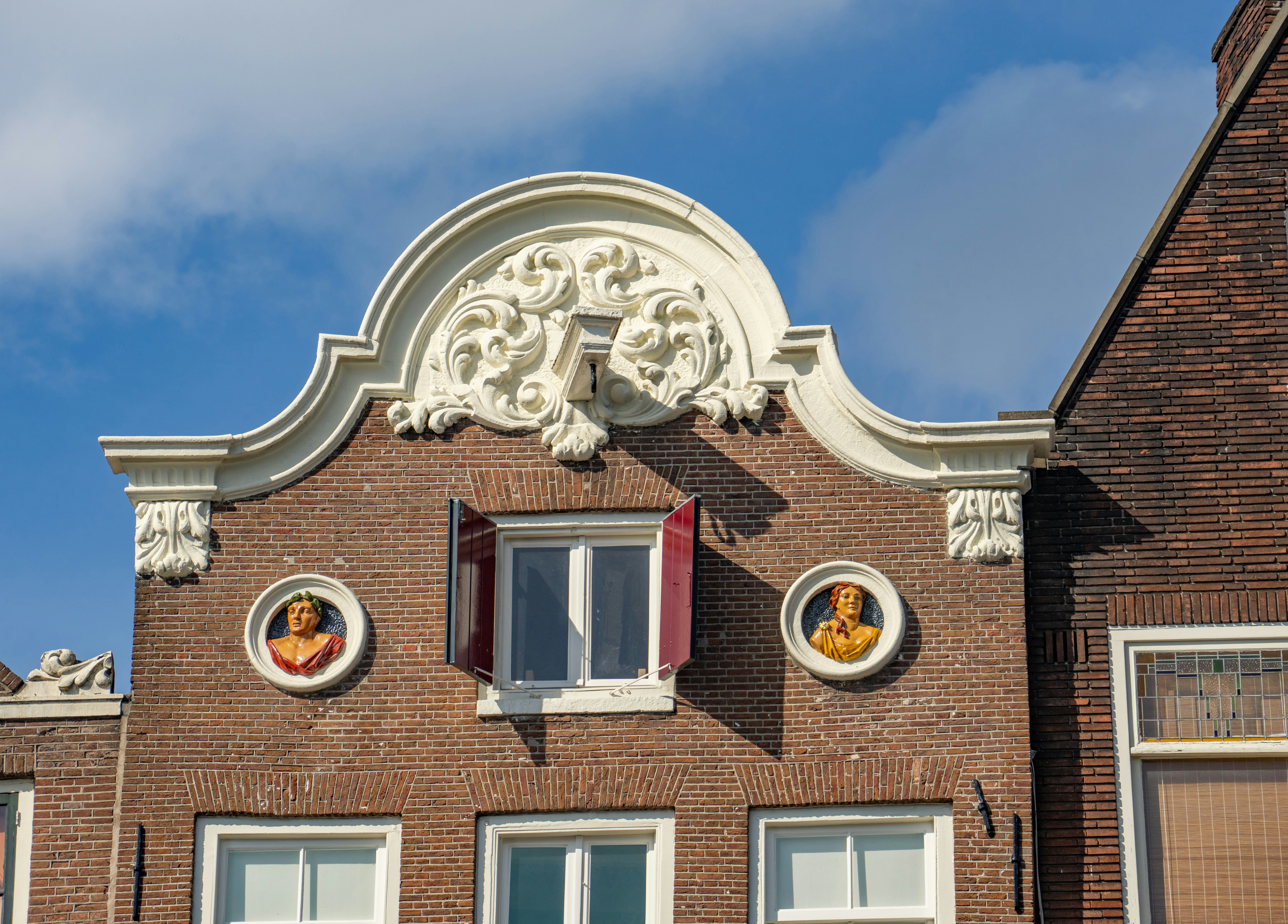 Historic building facade featuring sculpted figures above windows, showcasing intricate architectural details and vibrant colors.