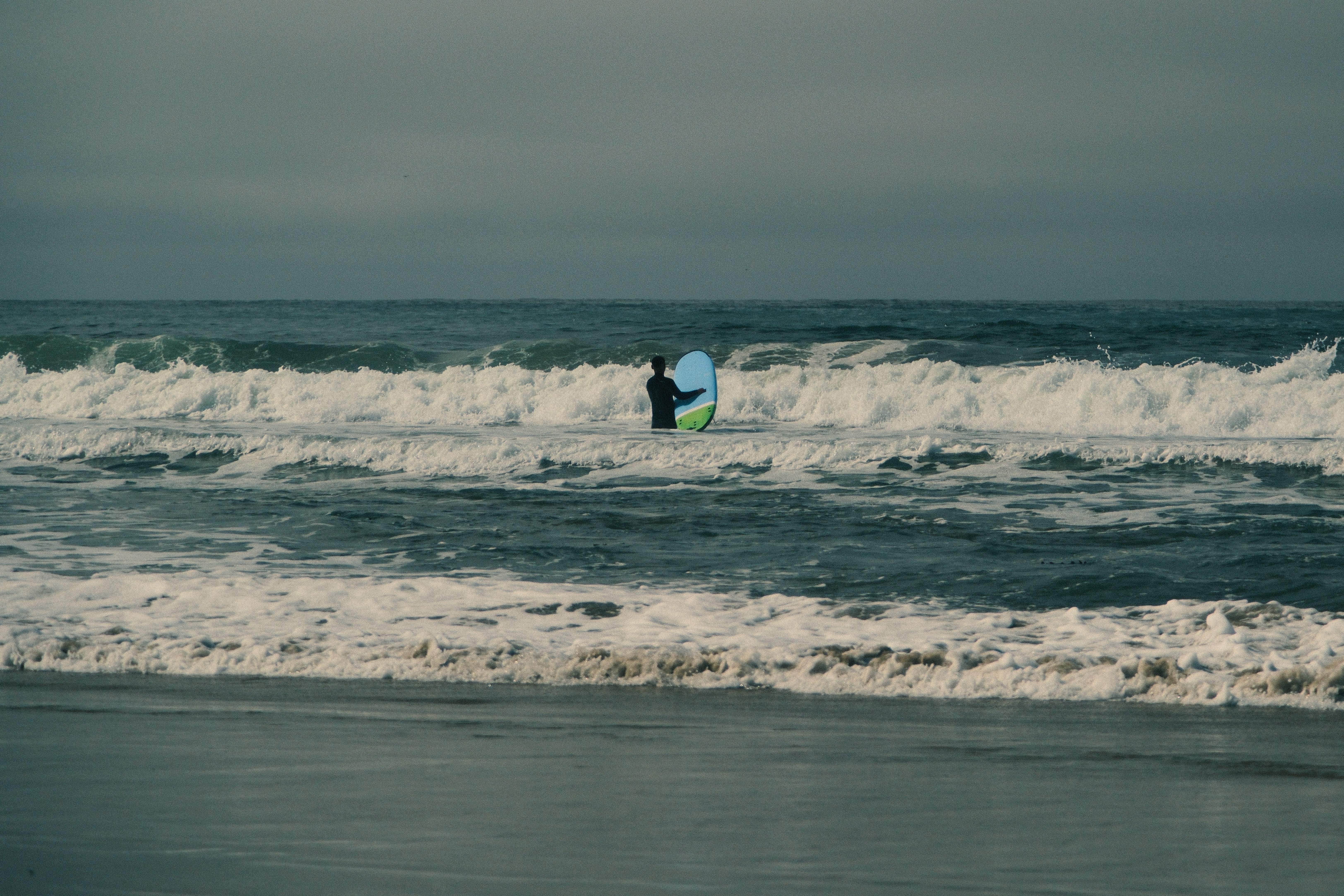 Surfer with surfboard entering the ocean waves