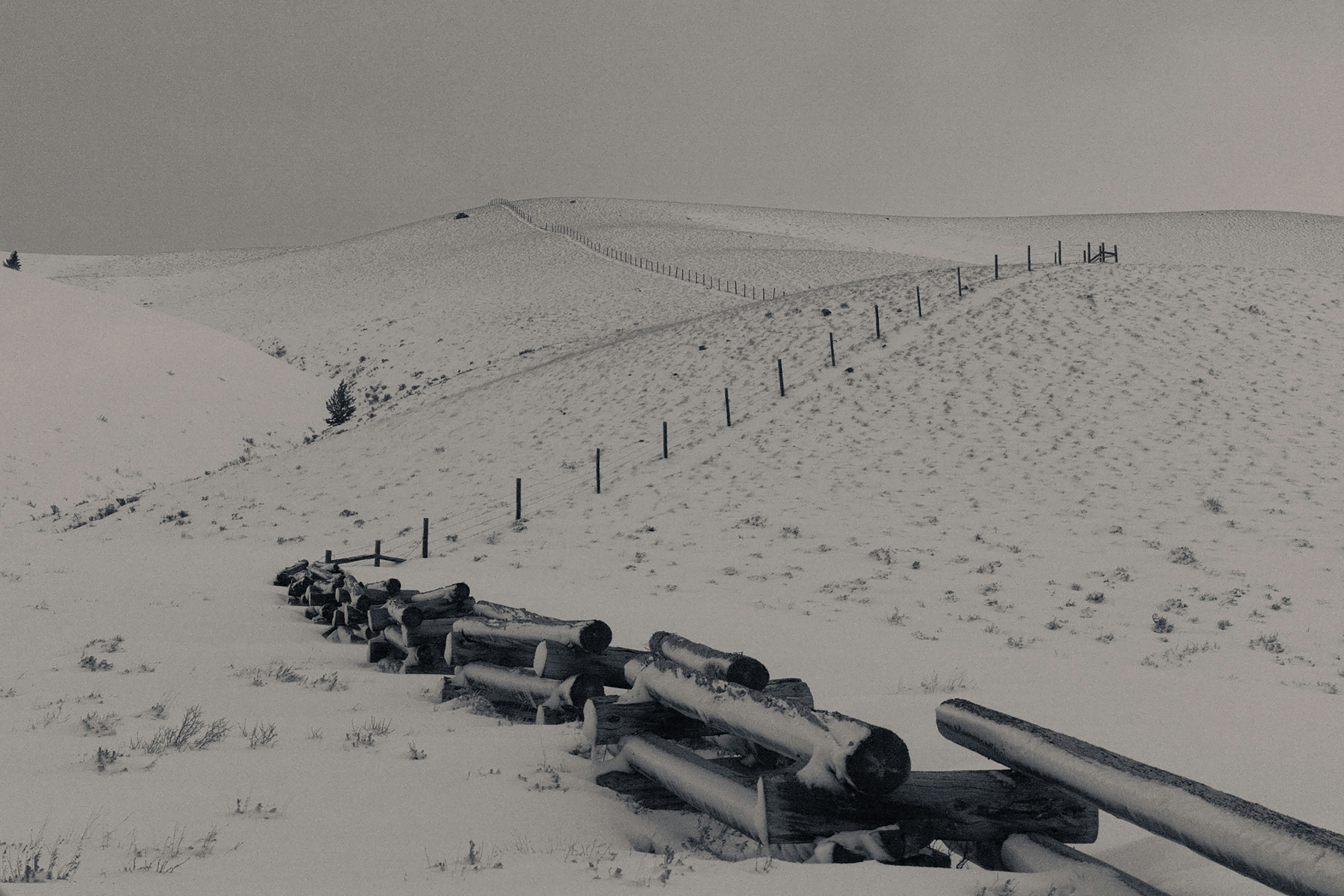 Snowy landscape with wooden fence and rolling hills