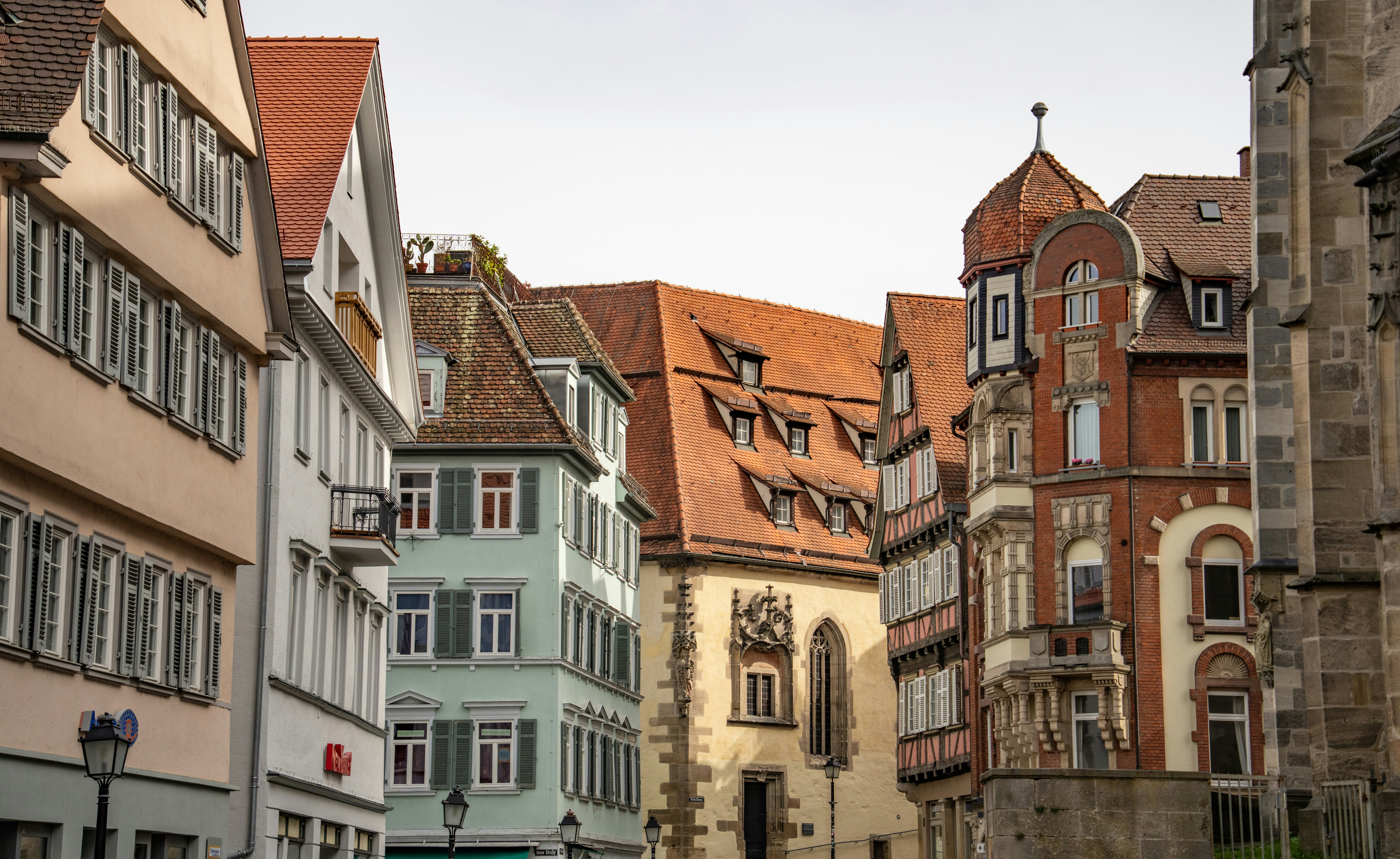 Historic buildings with varied architectural styles converge in a charming street scene, showcasing intricate facades and rooftops. The interplay of light highlights the details of each structure.