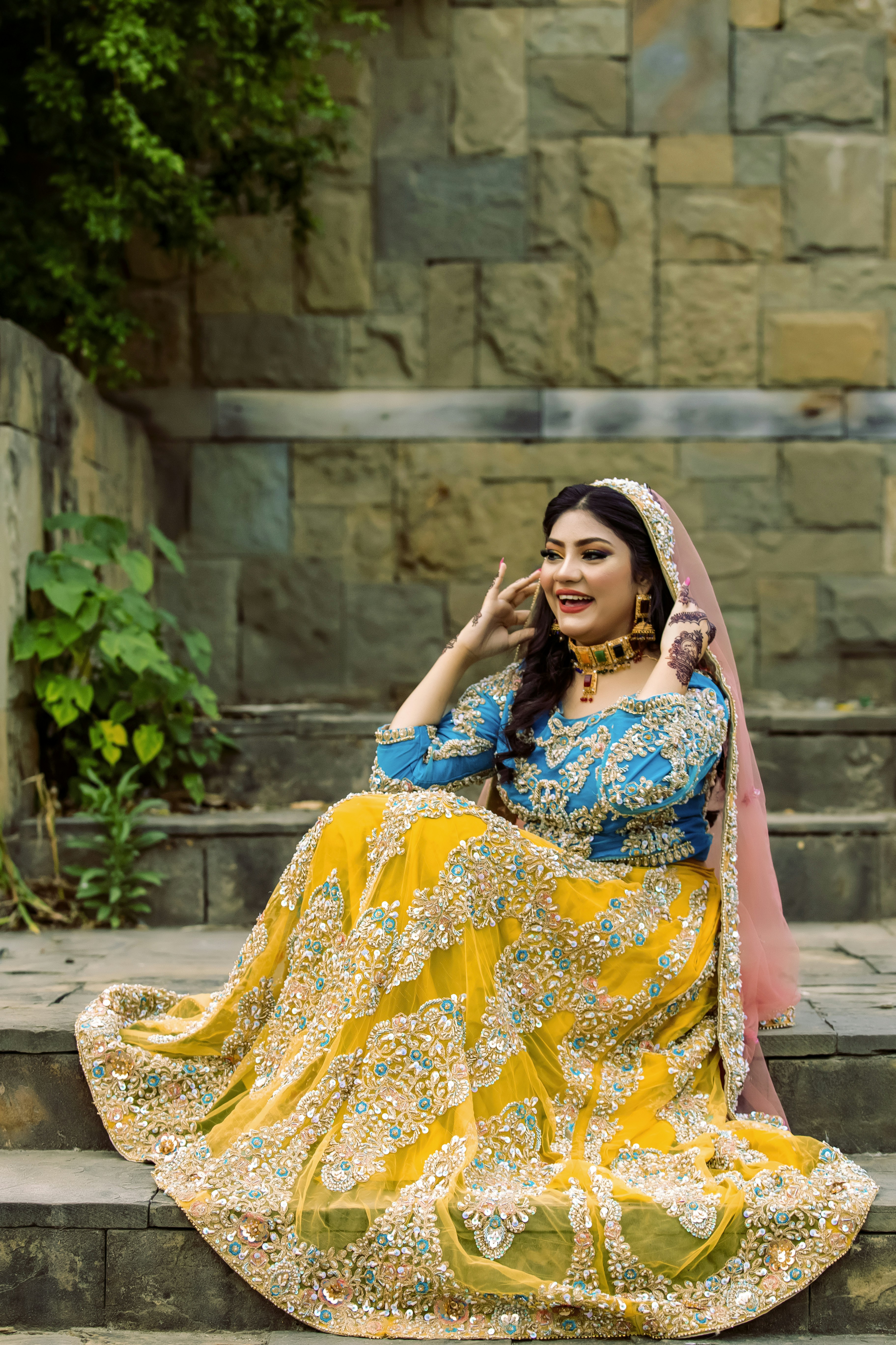 A woman in a colorful traditional outfit sits on stairs.