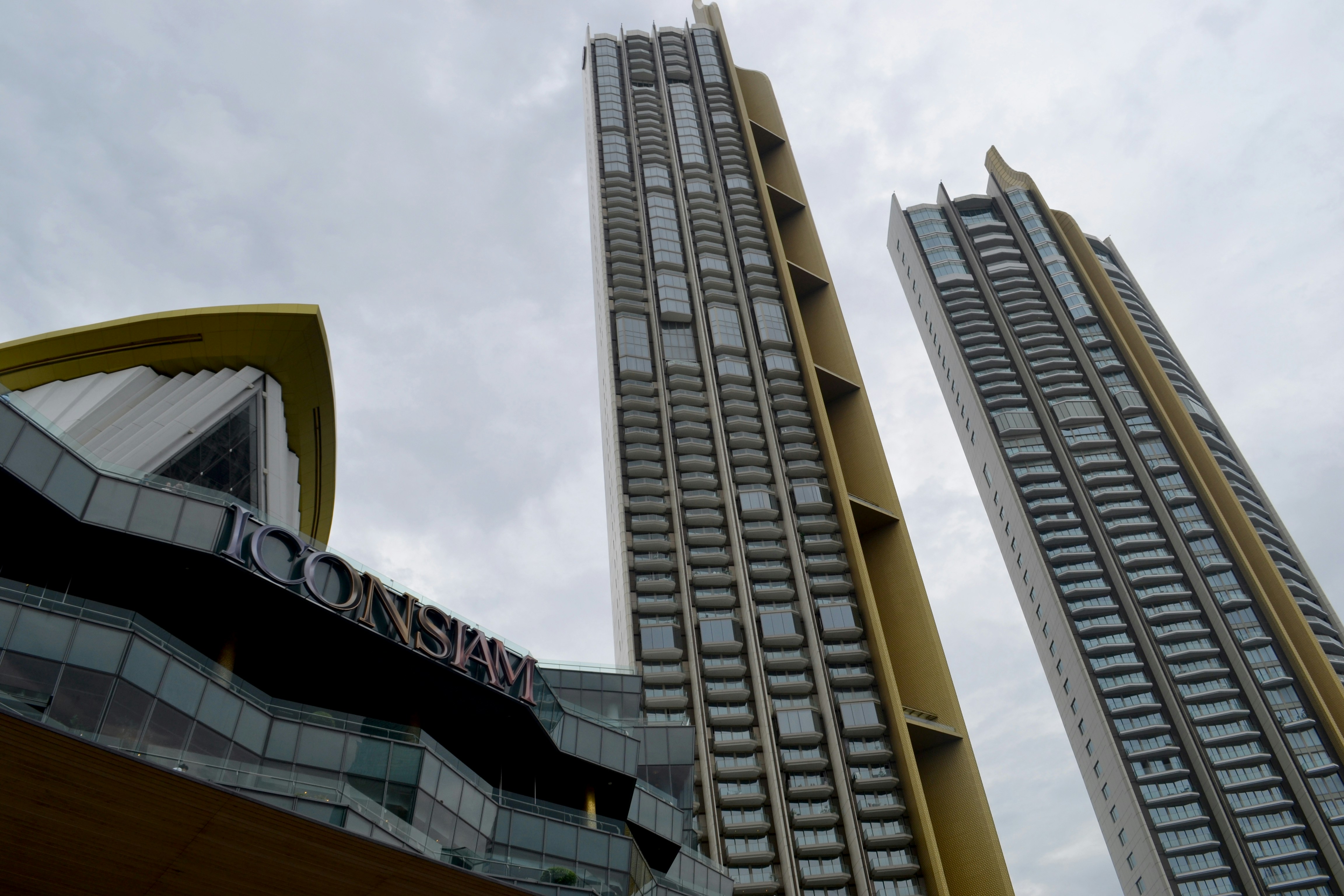Tall, sleek skyscrapers rise against a cloudy sky, showcasing contemporary design elements and urban sophistication.