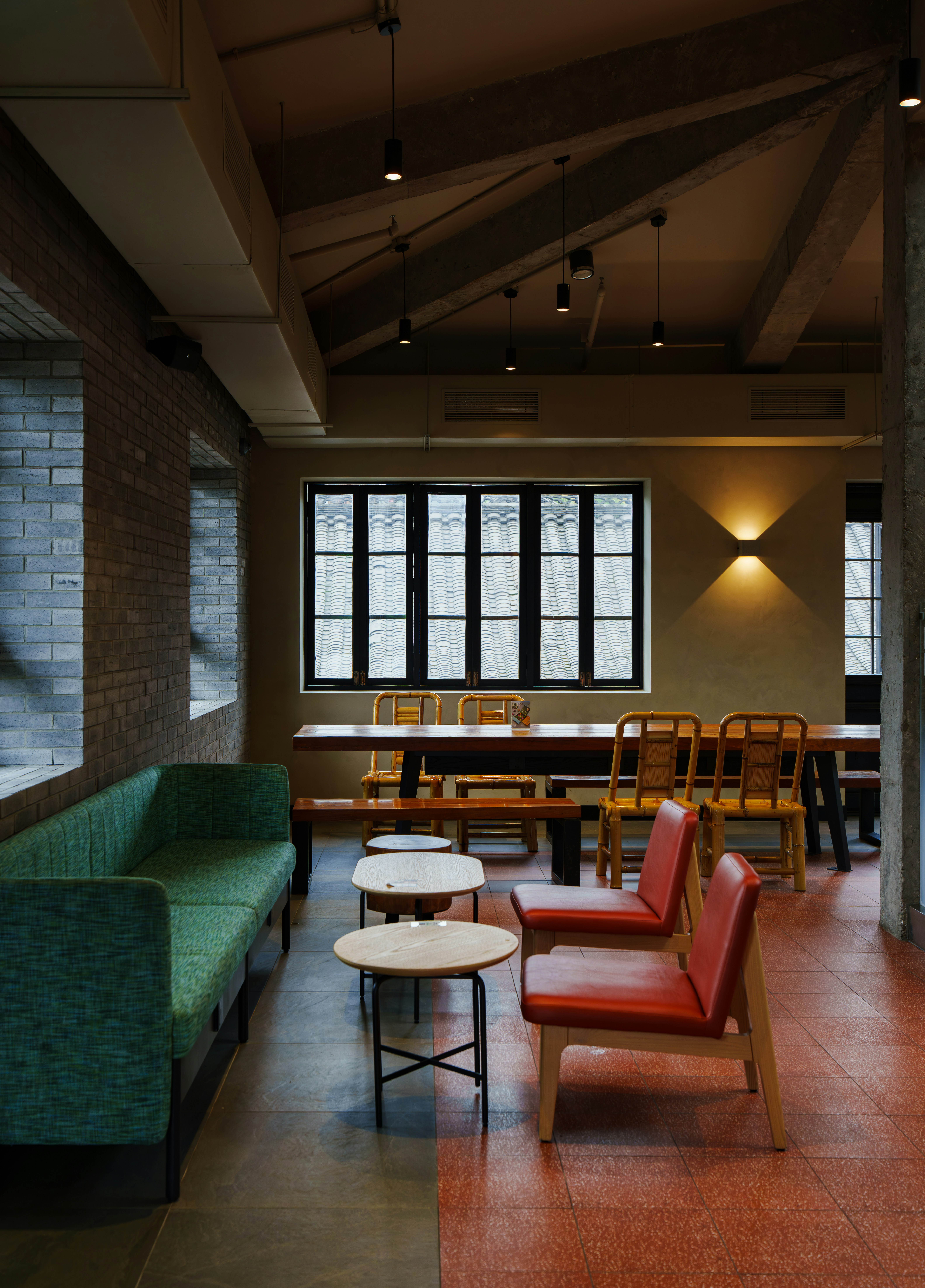 Modern lounge area with green sofa and red chairs.
