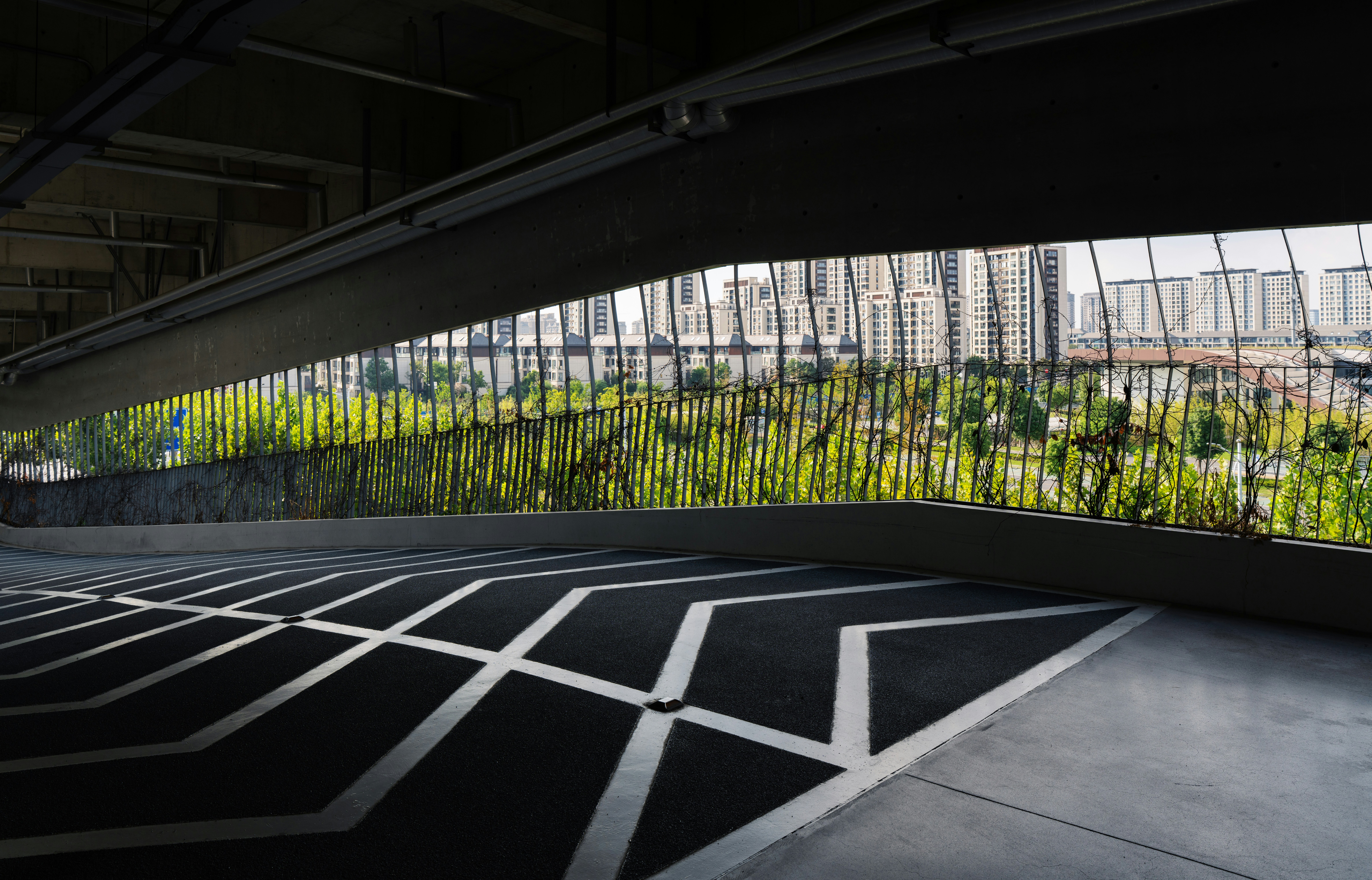 Abstract patterns of parking lines converge towards a window revealing a cityscape beyond. The interplay of architecture and nature creates a dynamic urban scene.