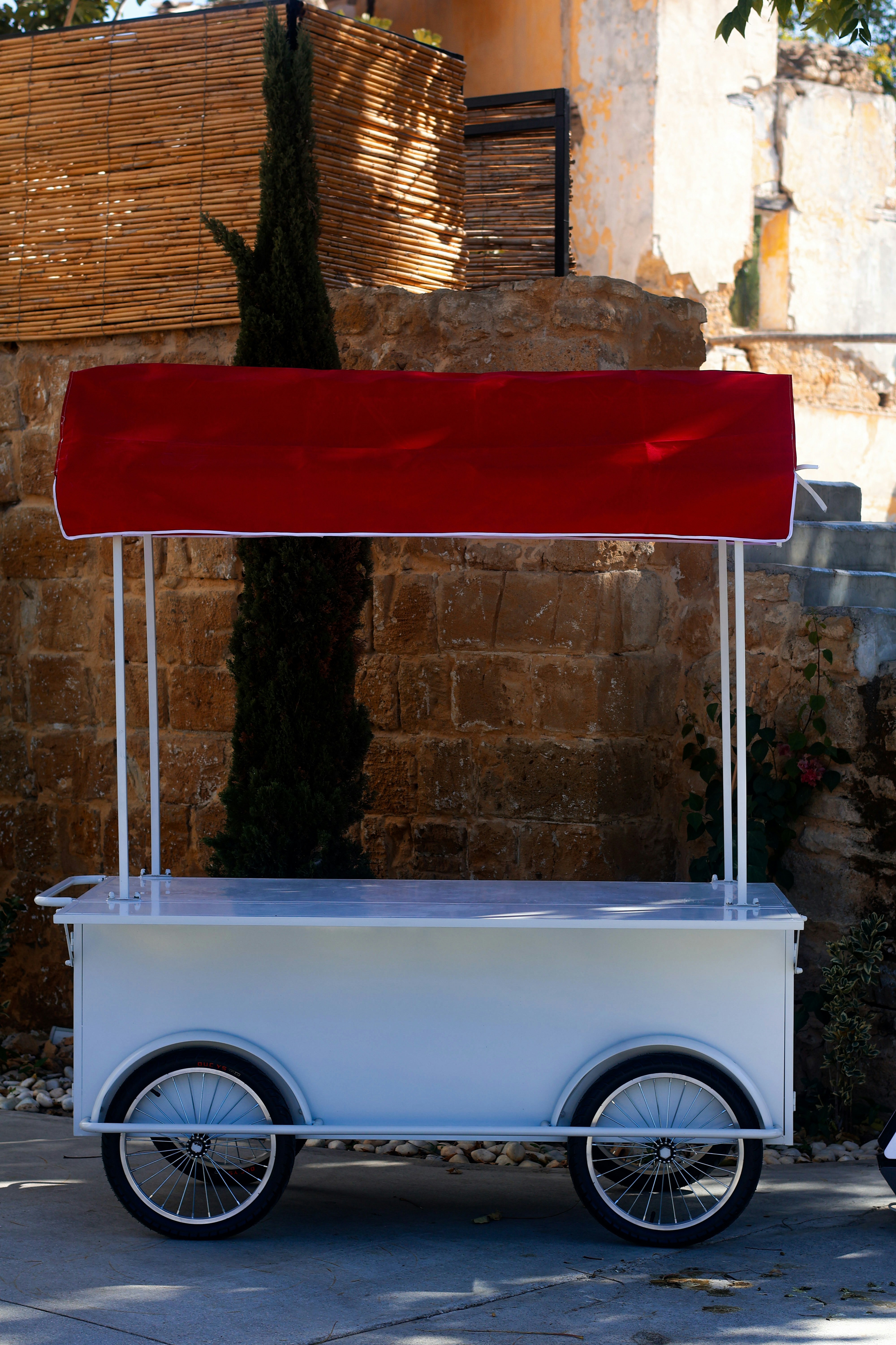 Empty white food cart with red canopy