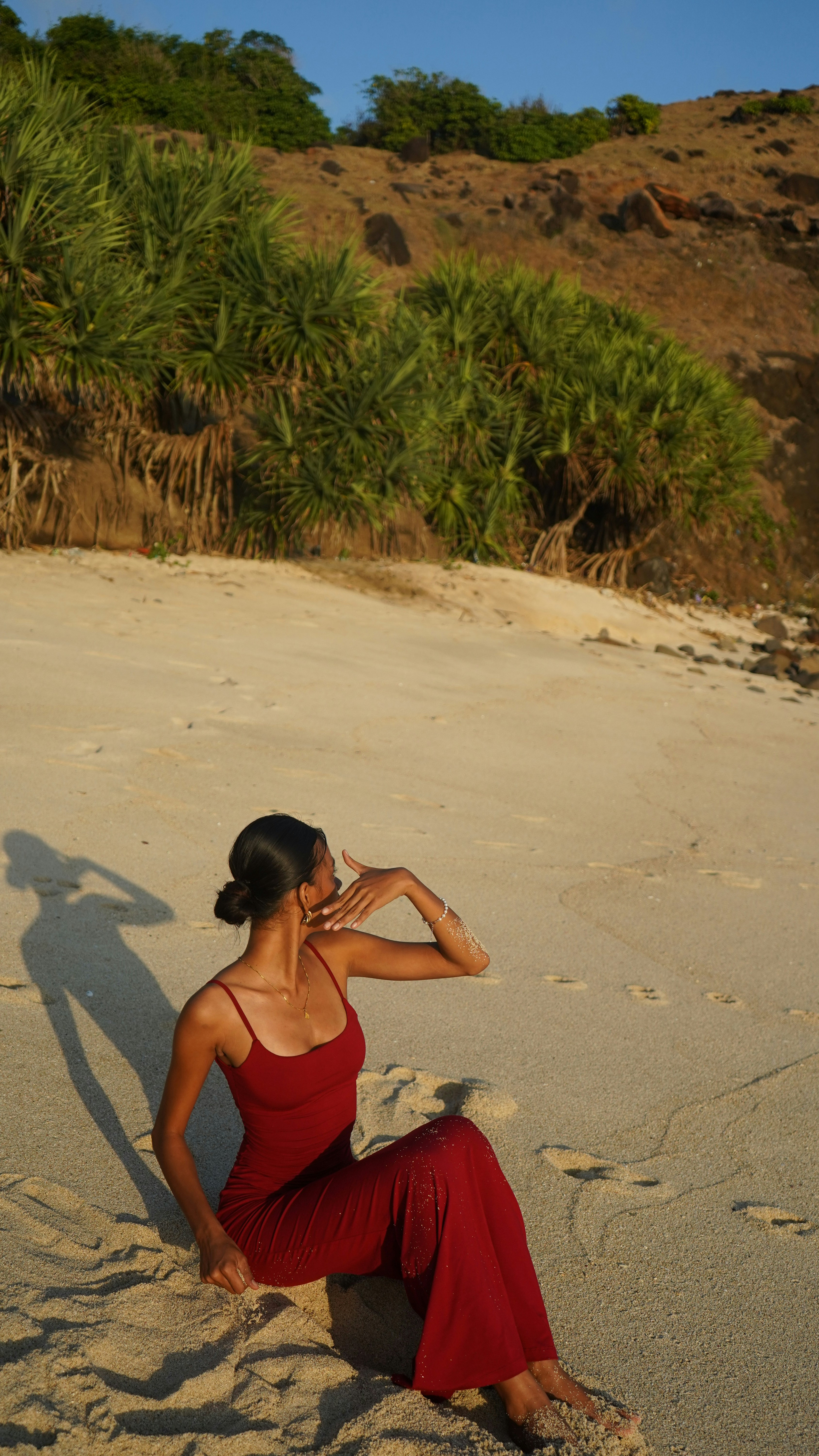Beautiful girl in red dress on white sand beach. | Woman in red dress on sandy beach at sunset