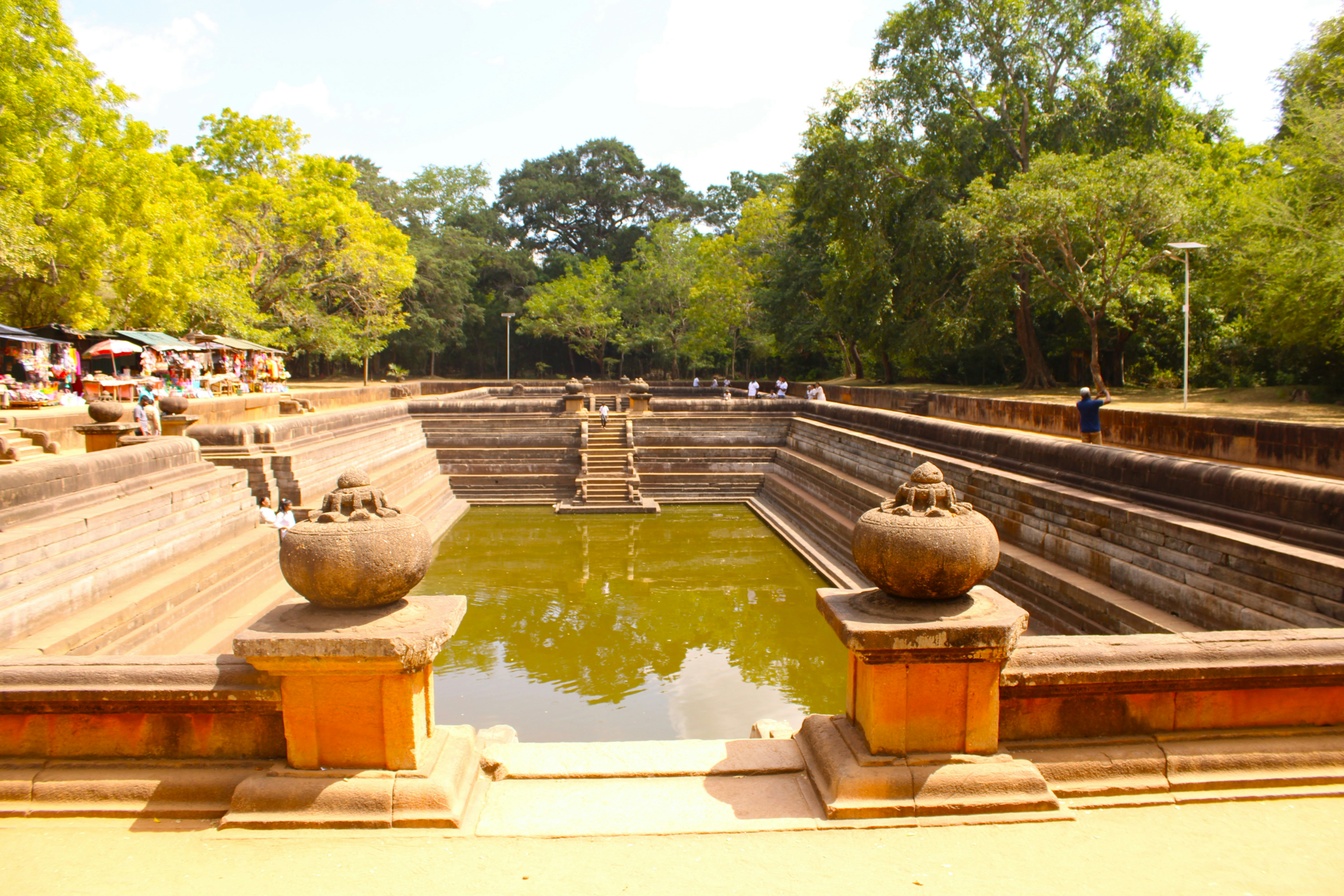 Ancient stone bathing pond with stairs and trees.