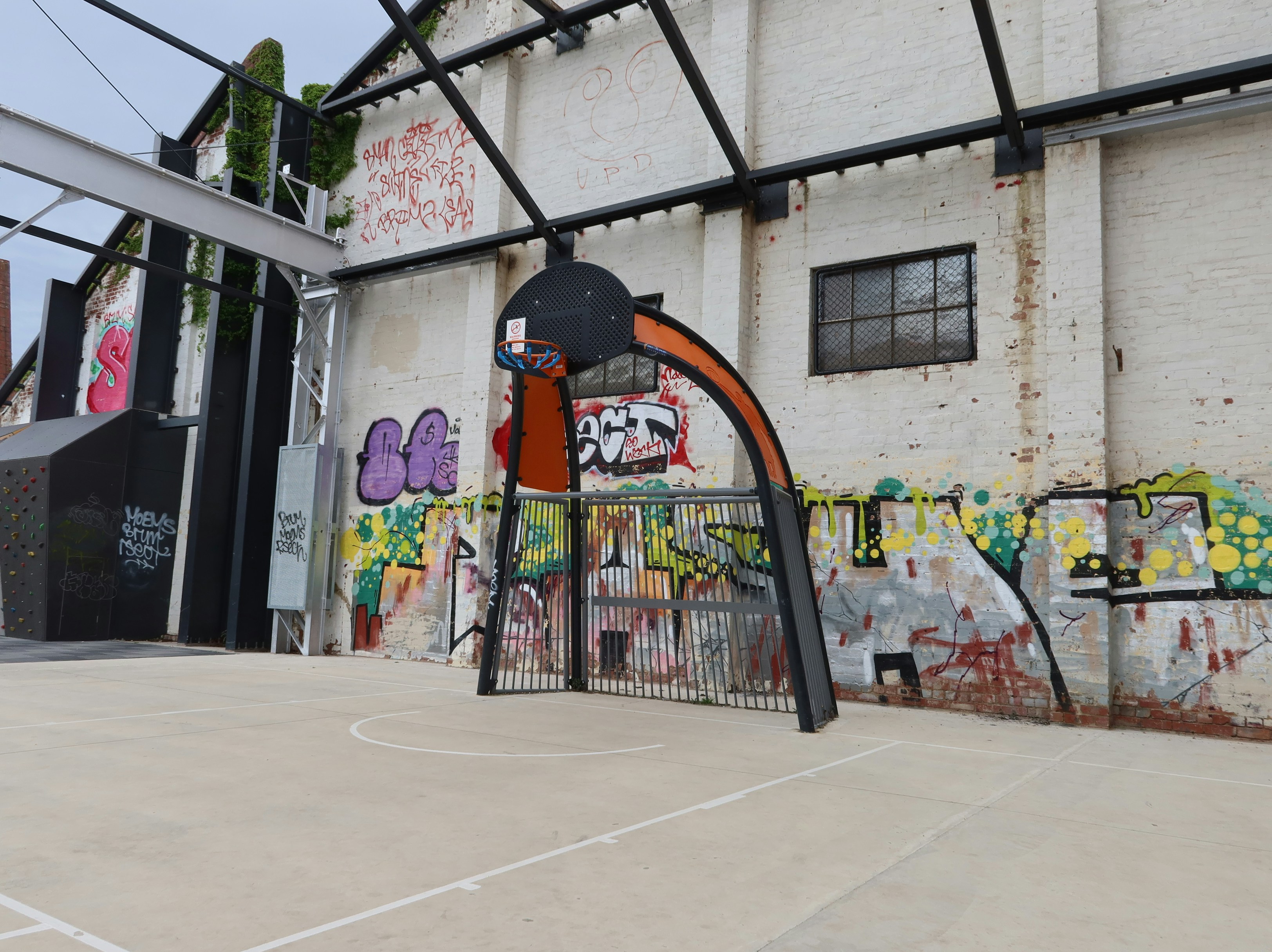 Graffiti-covered outdoor basketball court with hoop.