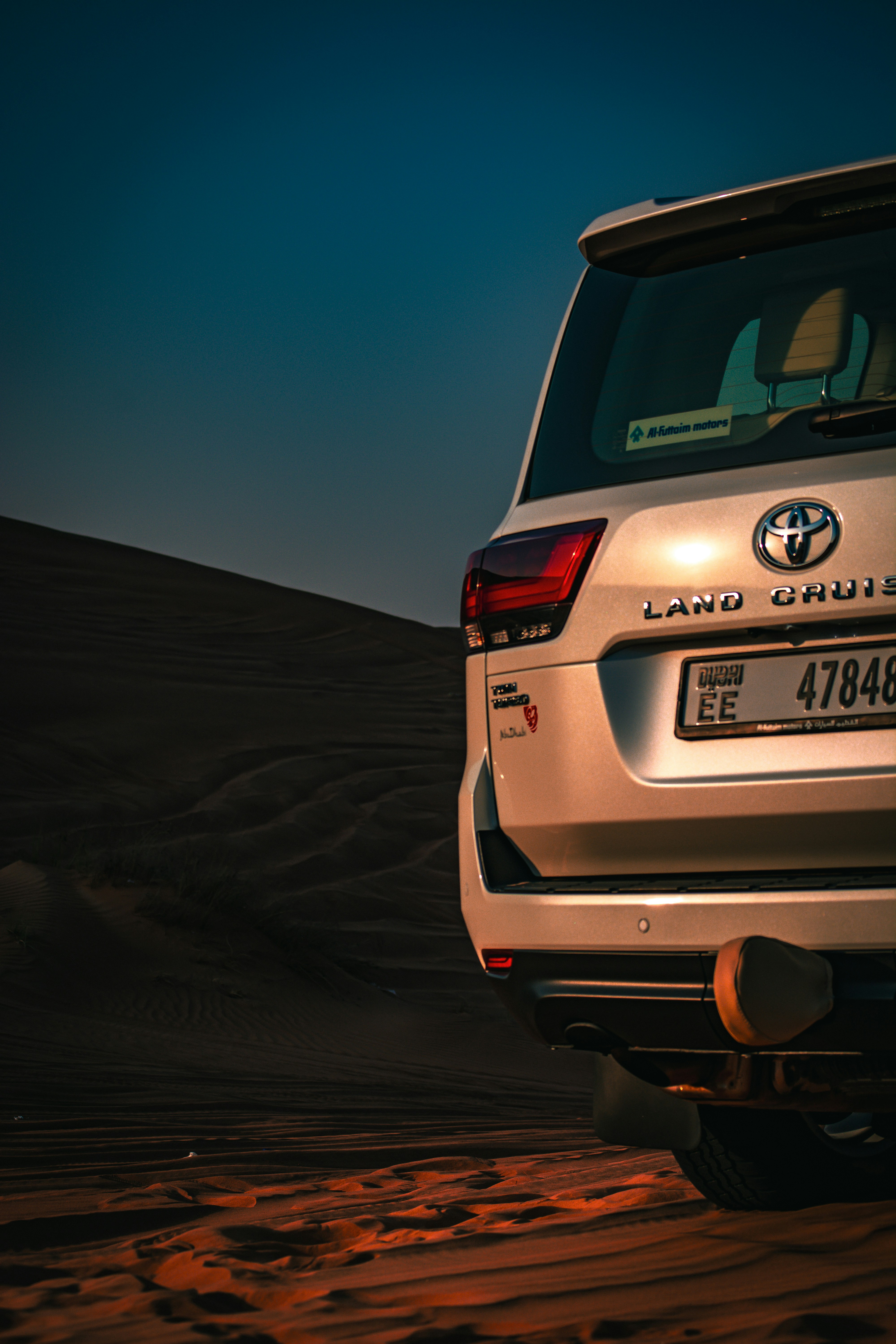 White toyota land cruiser driving on sand dunes.