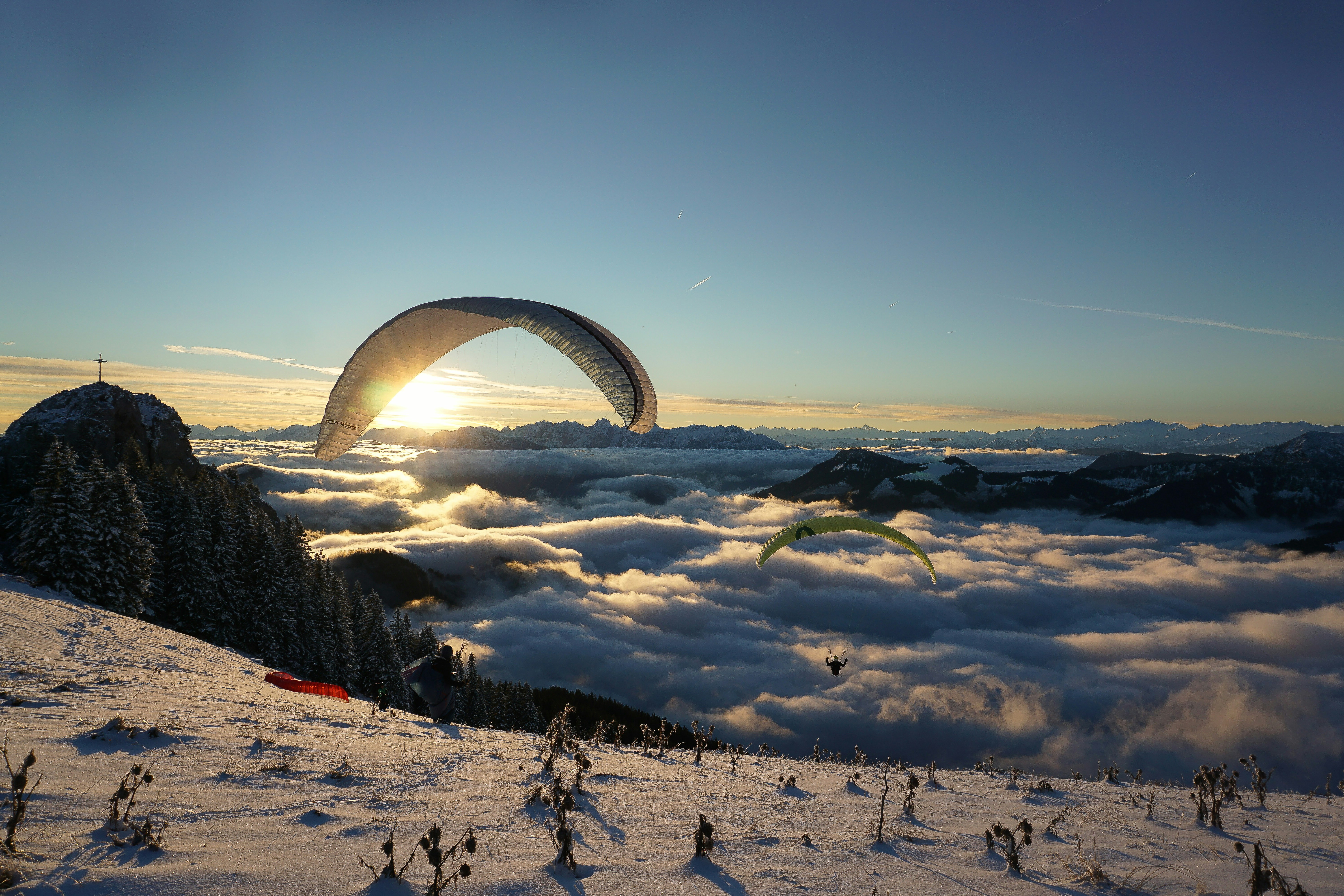 Paragliders soar above clouds at sunset