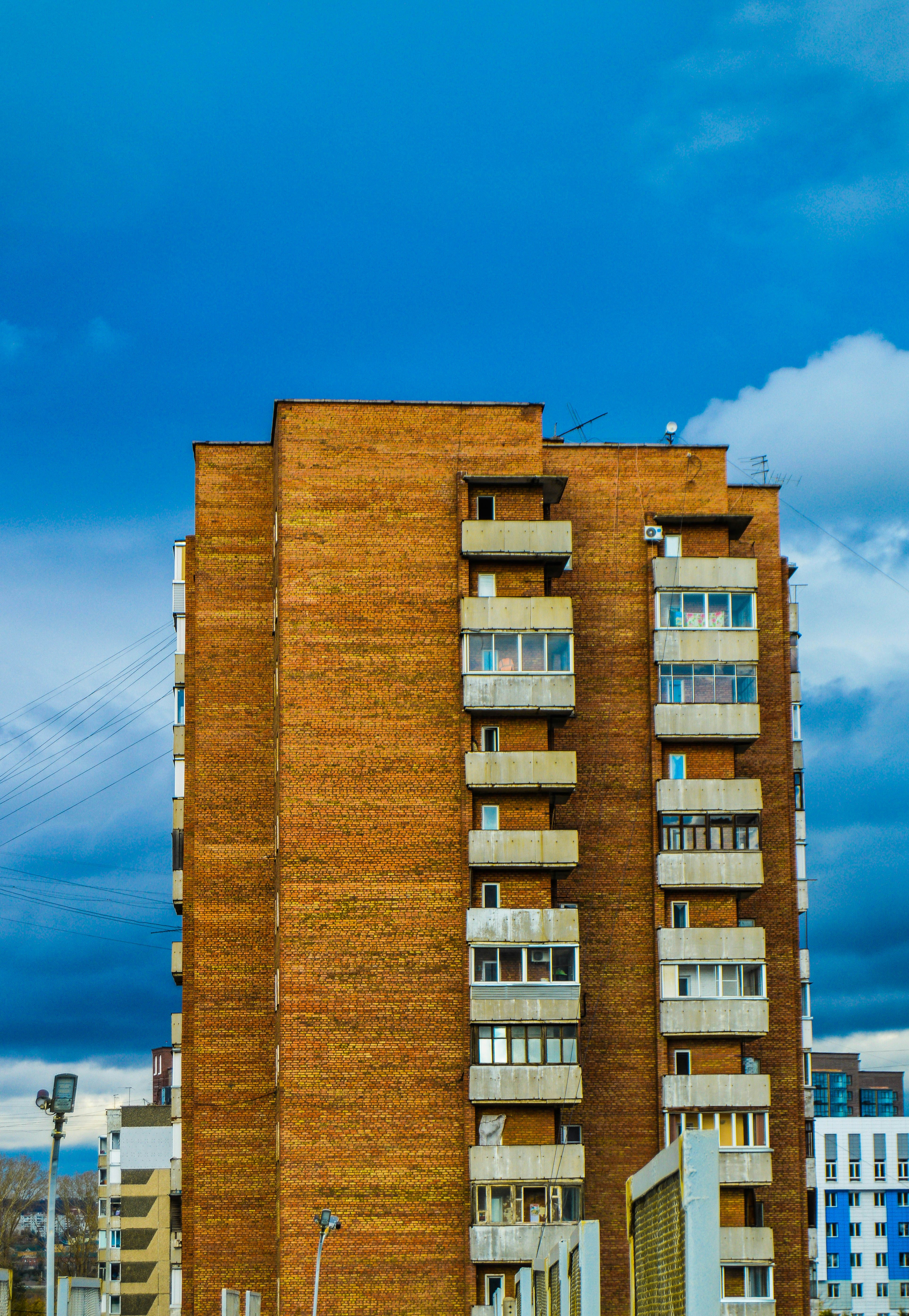 build house | Tall brick apartment building under a cloudy sky