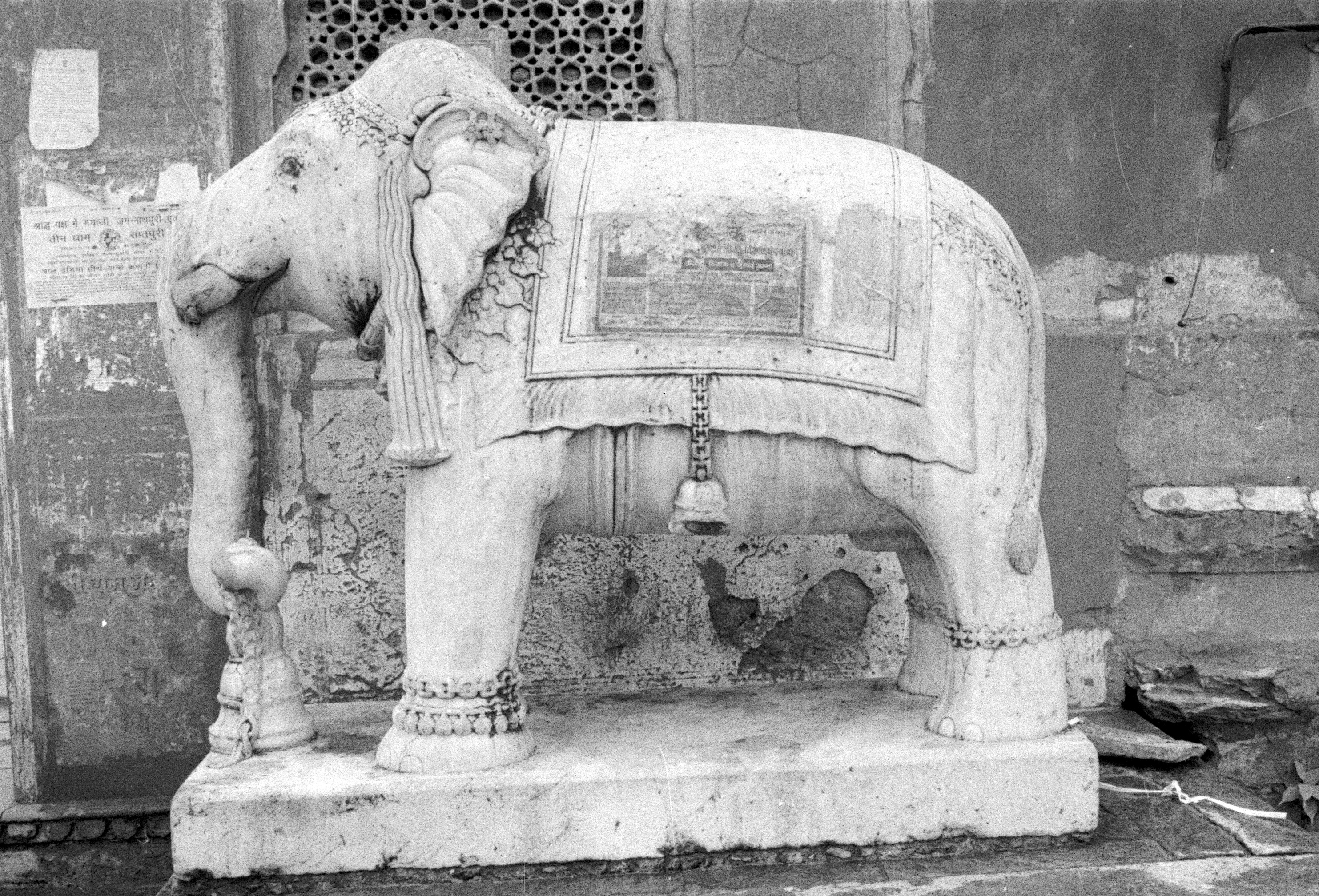 Stone elephant sculpture with ornate saddle and bell